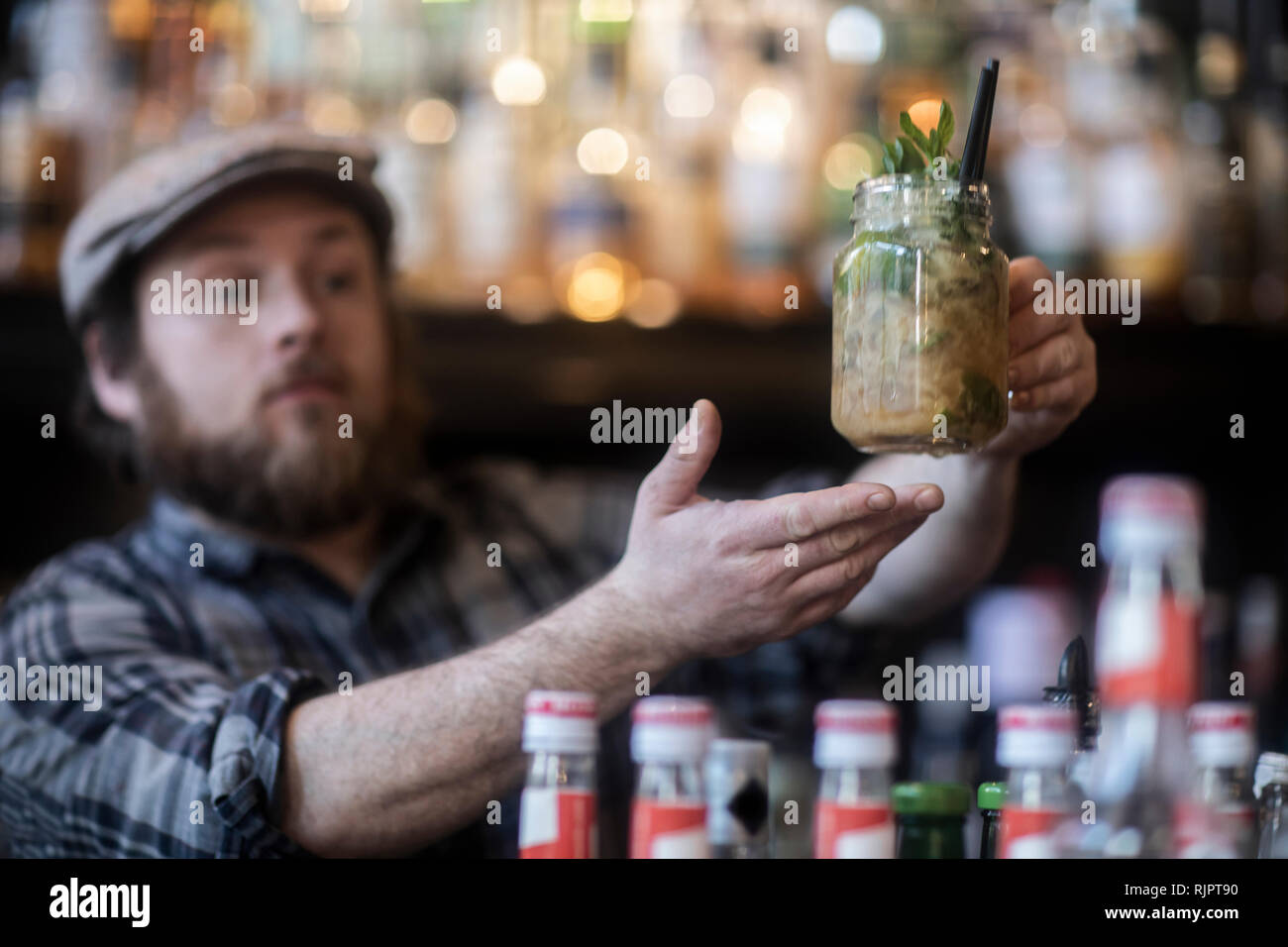 Barman serving jar glass cocktail in traditional Irish public house ...