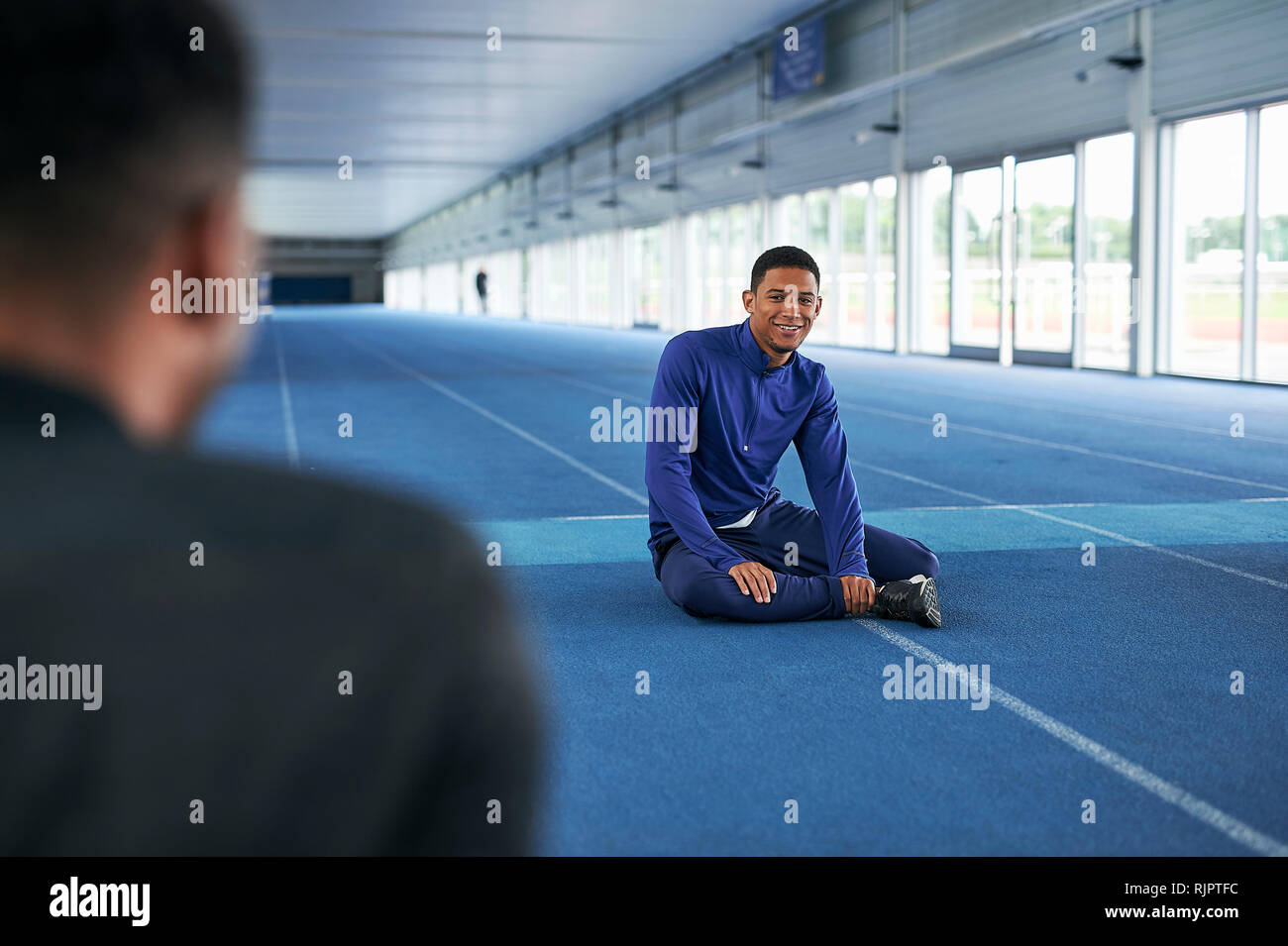 Runners sitting on indoor running track Stock Photo - Alamy