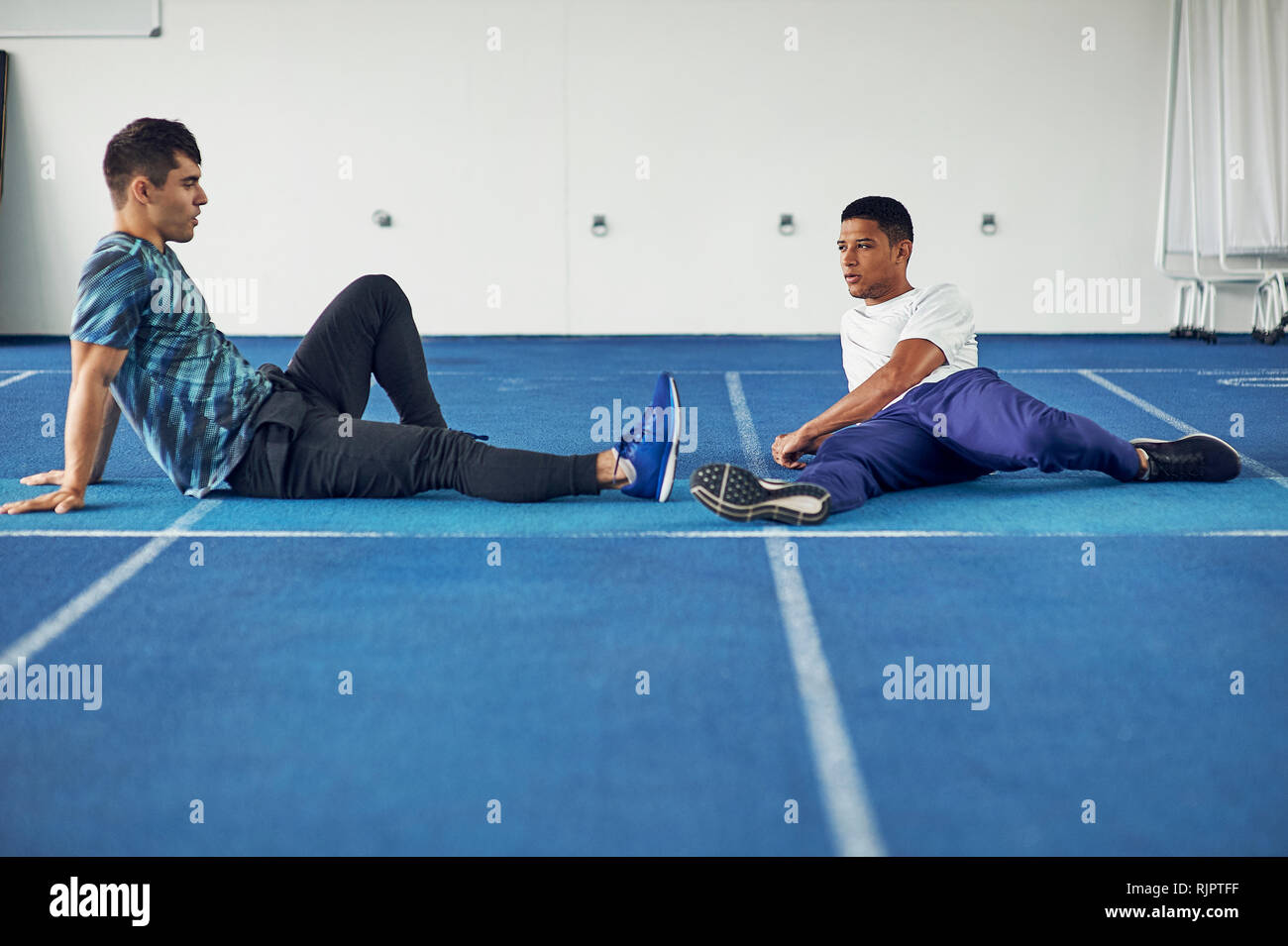 Runners sitting on indoor running track Stock Photo - Alamy