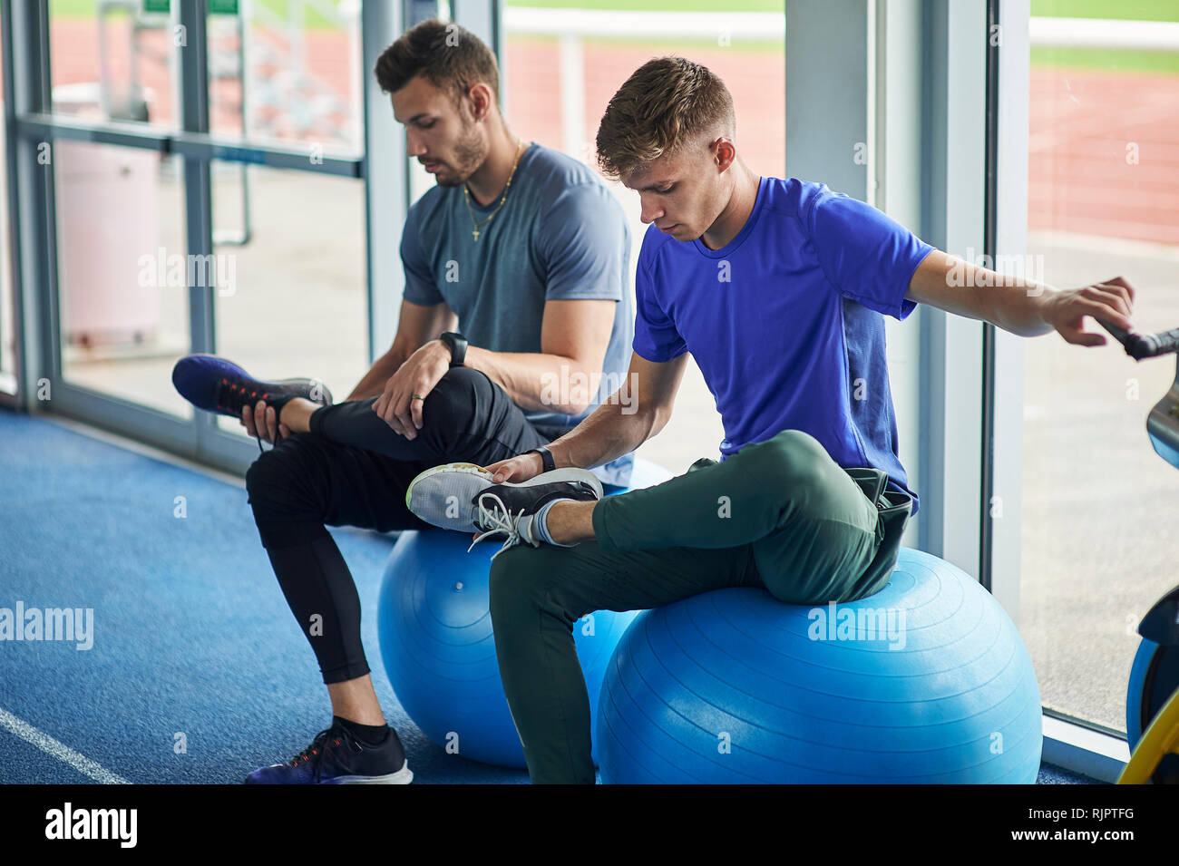 Runners stretching on exercise balls in indoor running track Stock ...