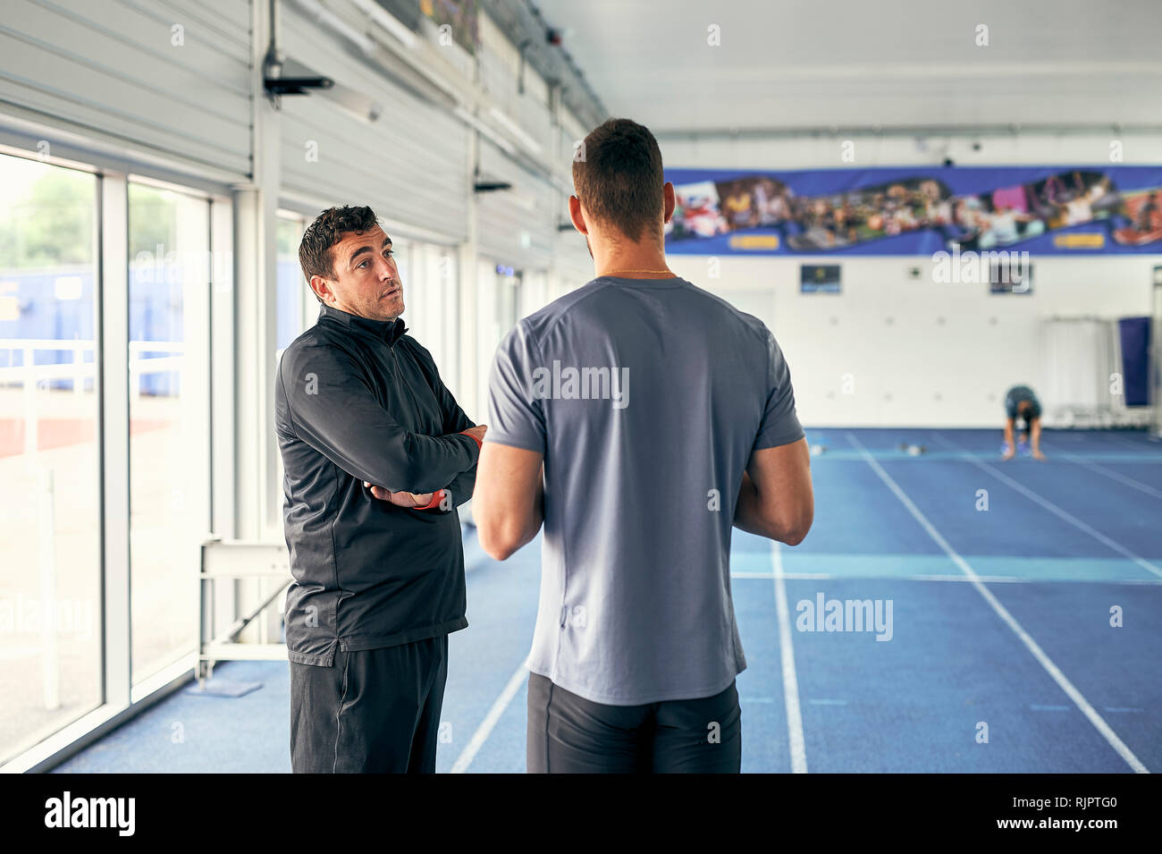Coach and runner speaking in indoor running track Stock Photo - Alamy