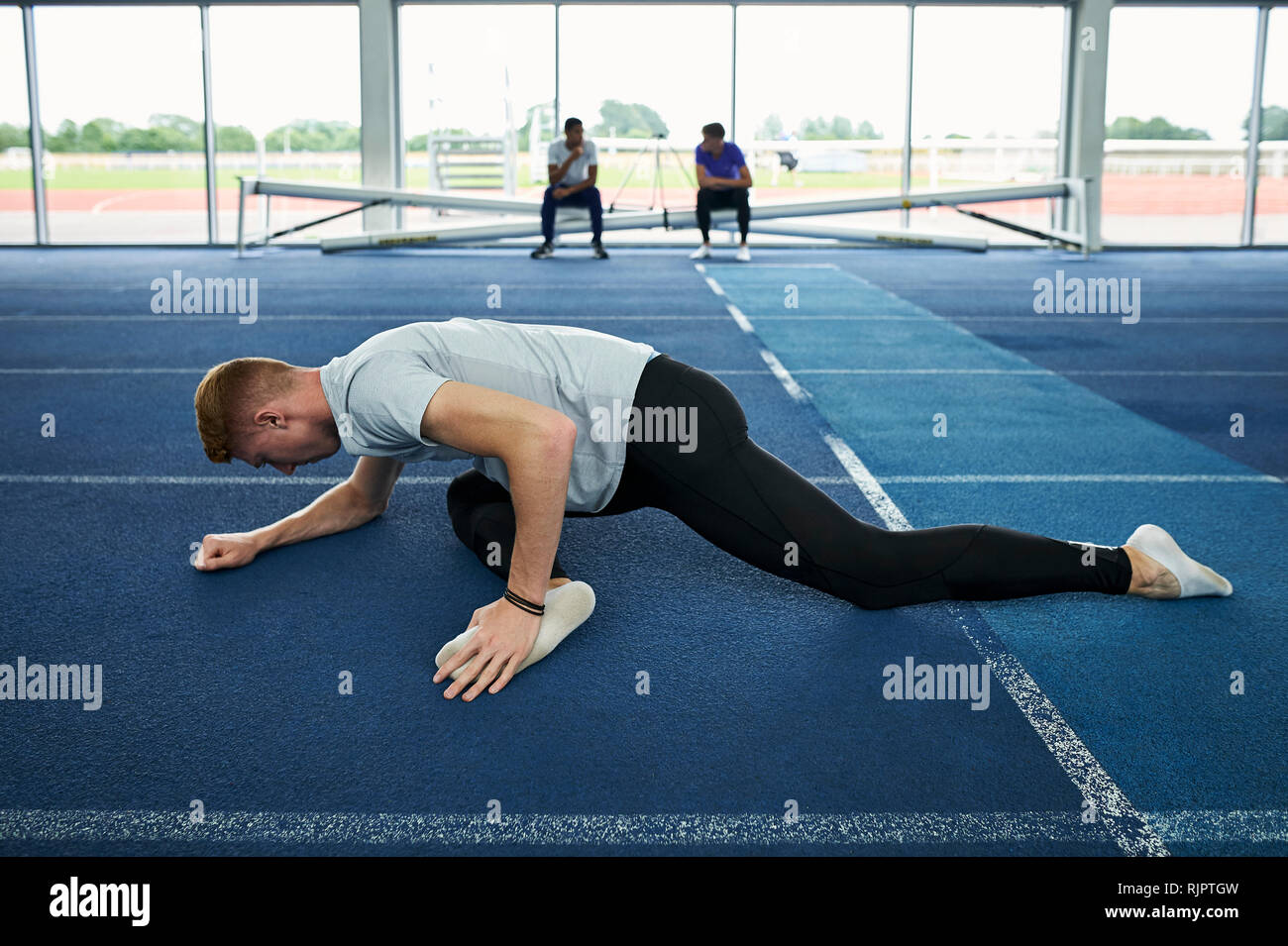 Runner stretching on indoor running track Stock Photo - Alamy