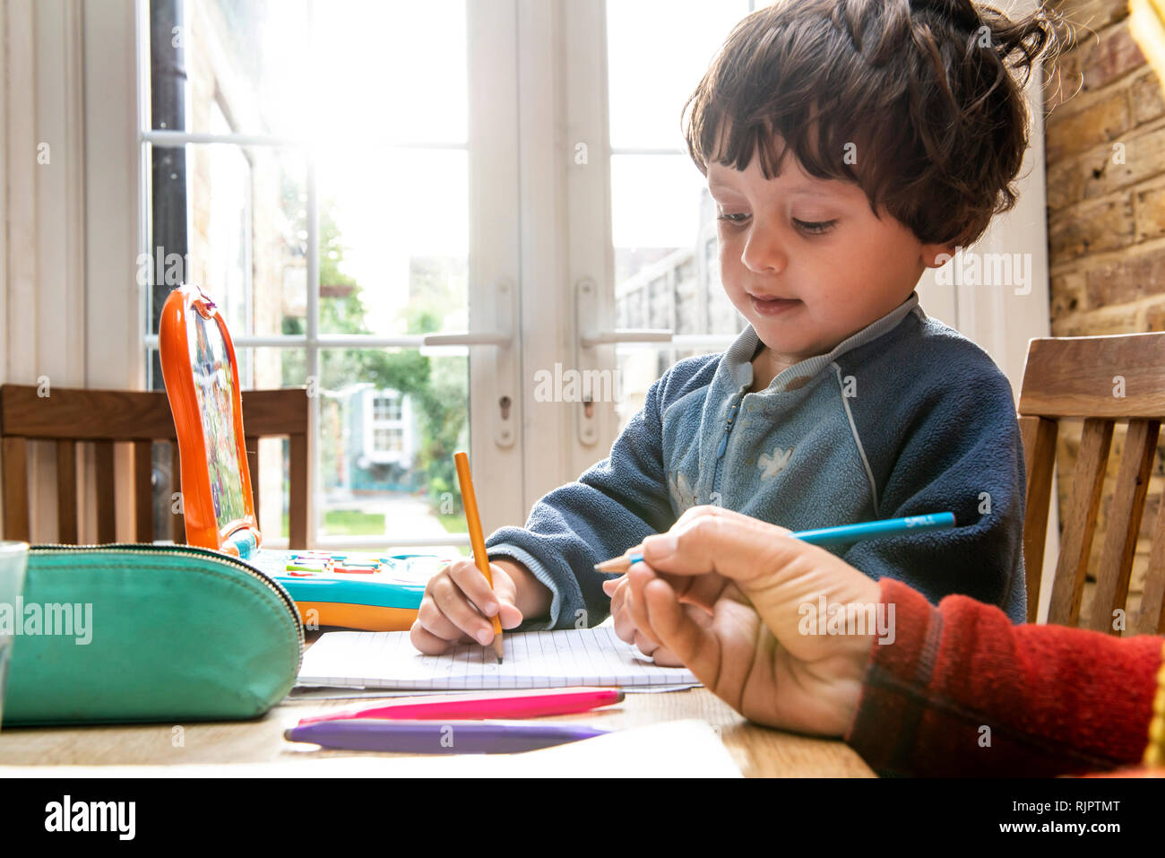 Mother and son writing in notebook Stock Photo - Alamy