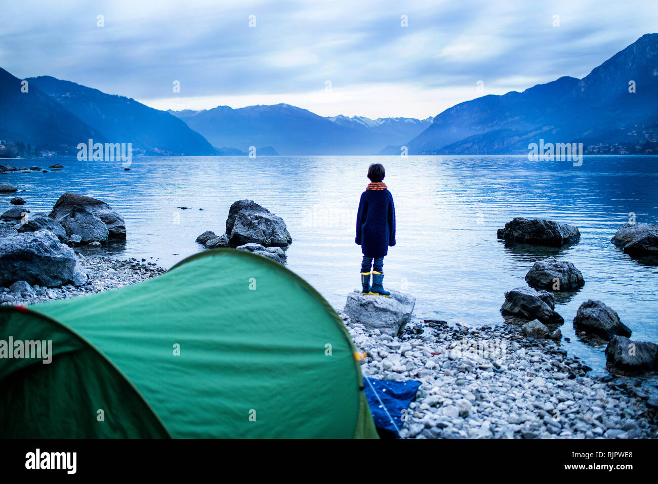 Boy looking out over lake, rear view, Lake Como, Onno, Lombardy, Italy ...
