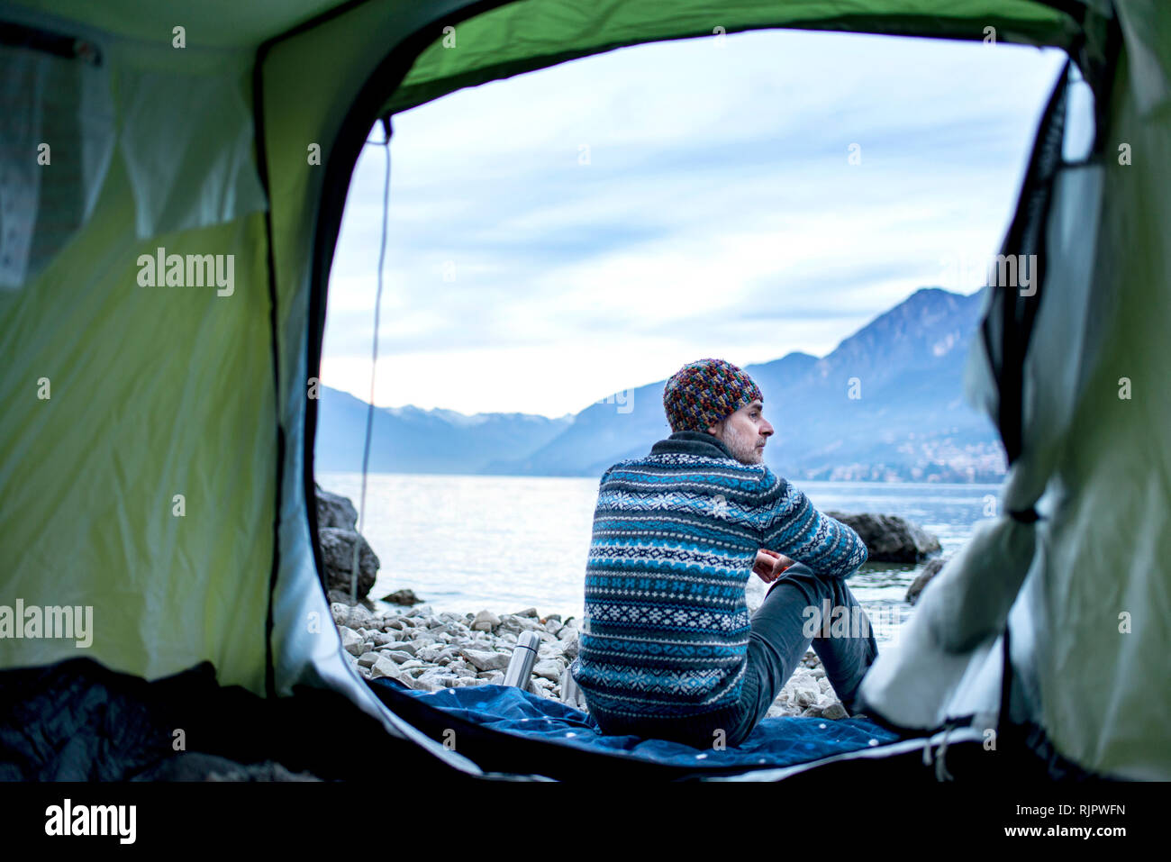 Man camping on lakeside, view from inside tent, Onno, Lombardy, Italy ...