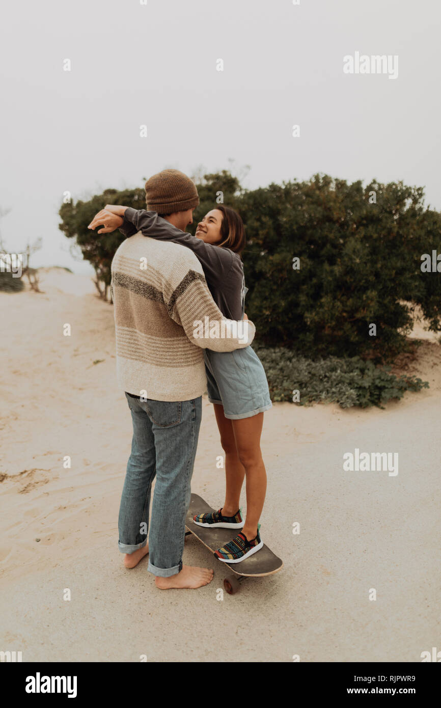 Romantic young skateboarding couple face to face on beach, Jalama ...