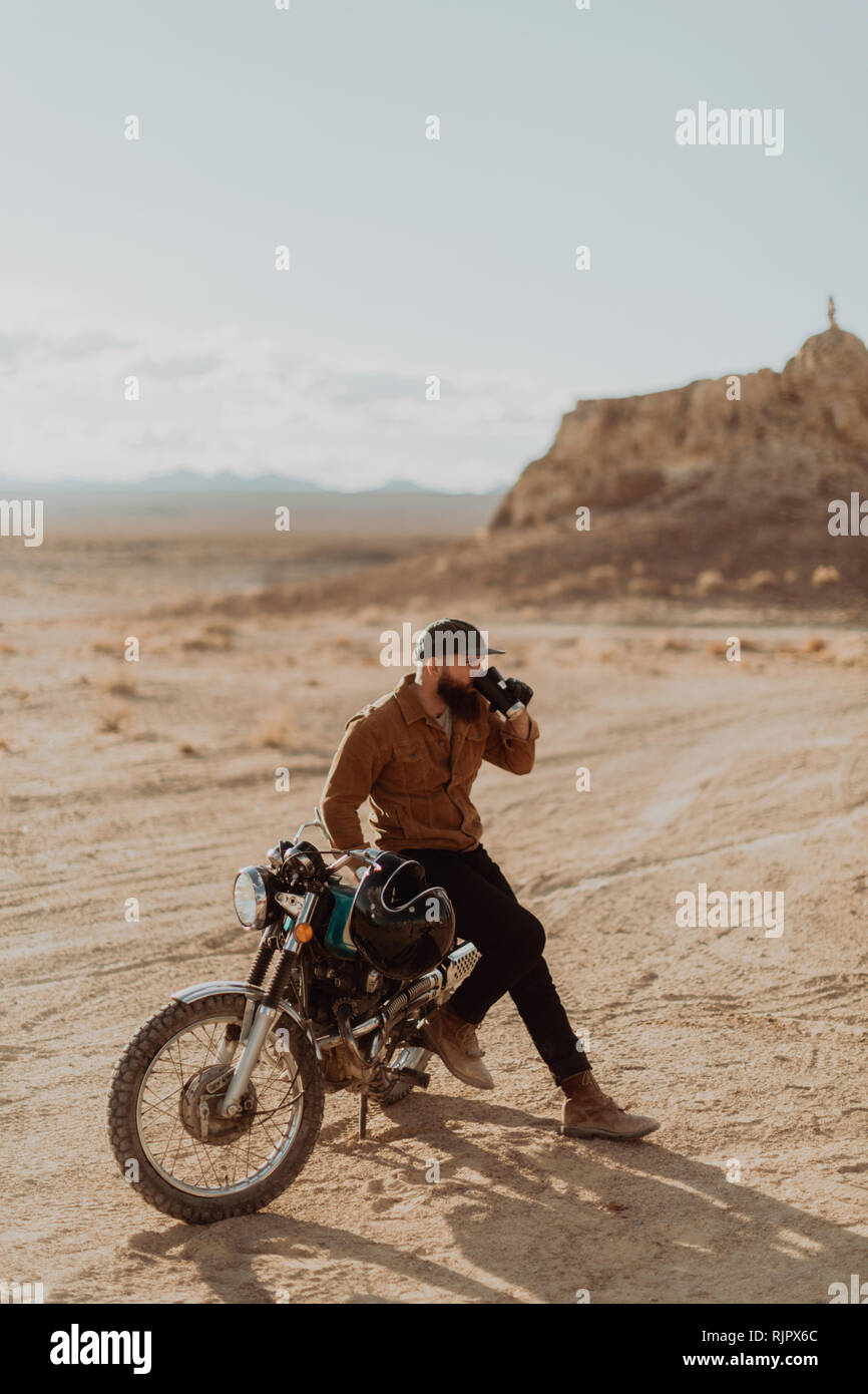 Motorcyclist enjoying drink on stationary bike, Trona Pinnacles ...