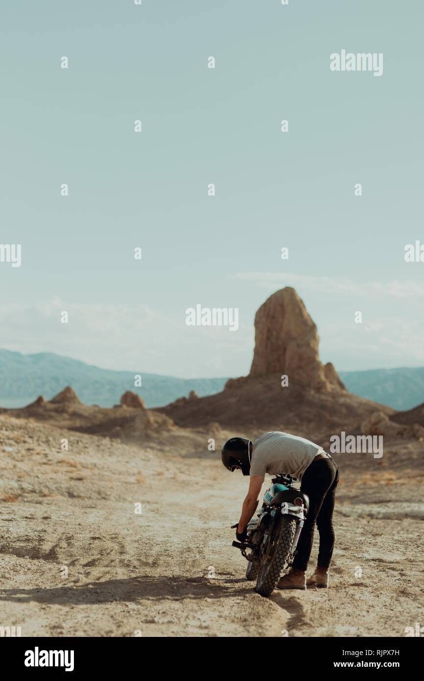 Motorcyclist bending over bike in desert, Trona Pinnacles, California ...
