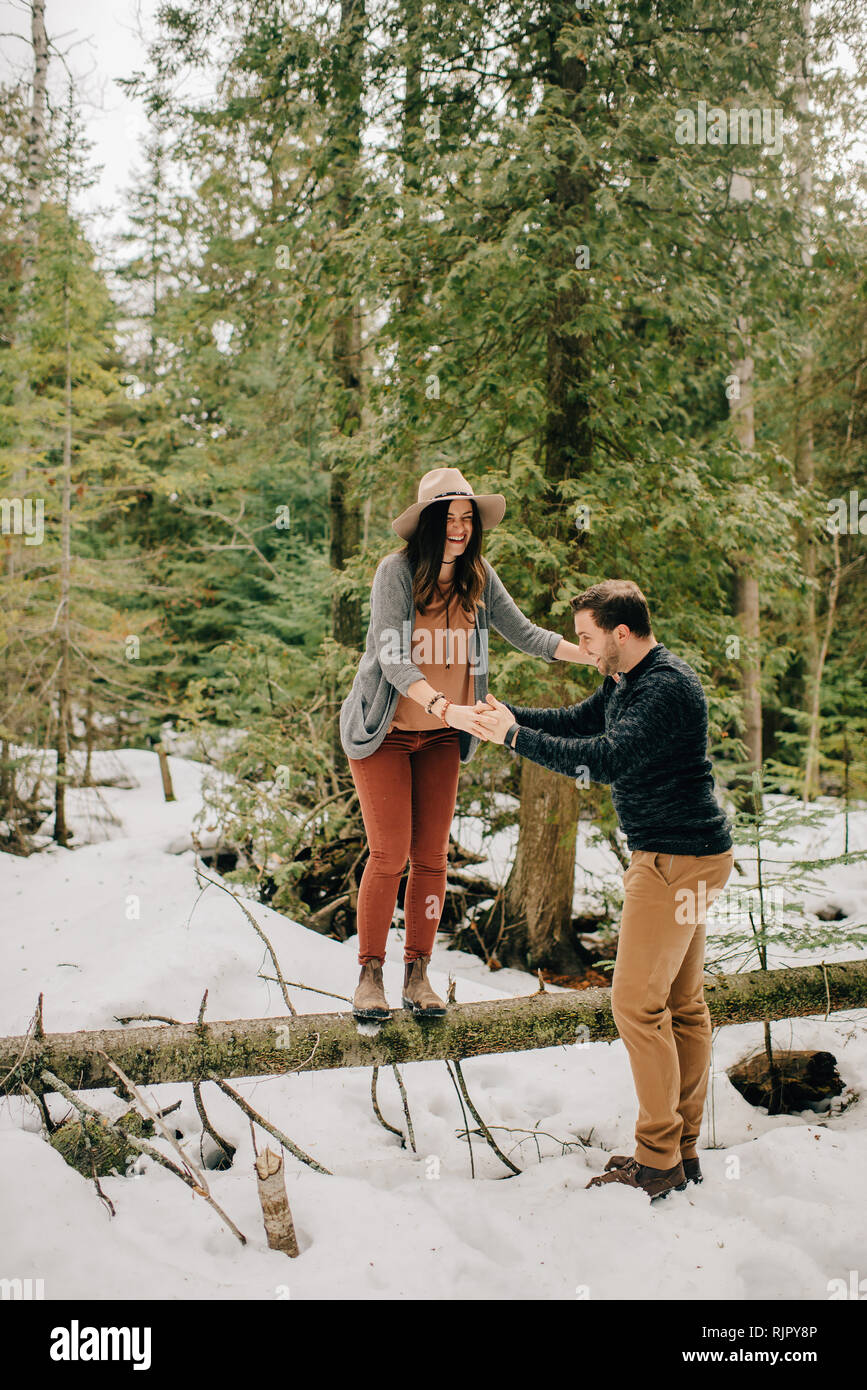 Couple crossing over fallen tree trunk in forest, Tobermory, Canada ...