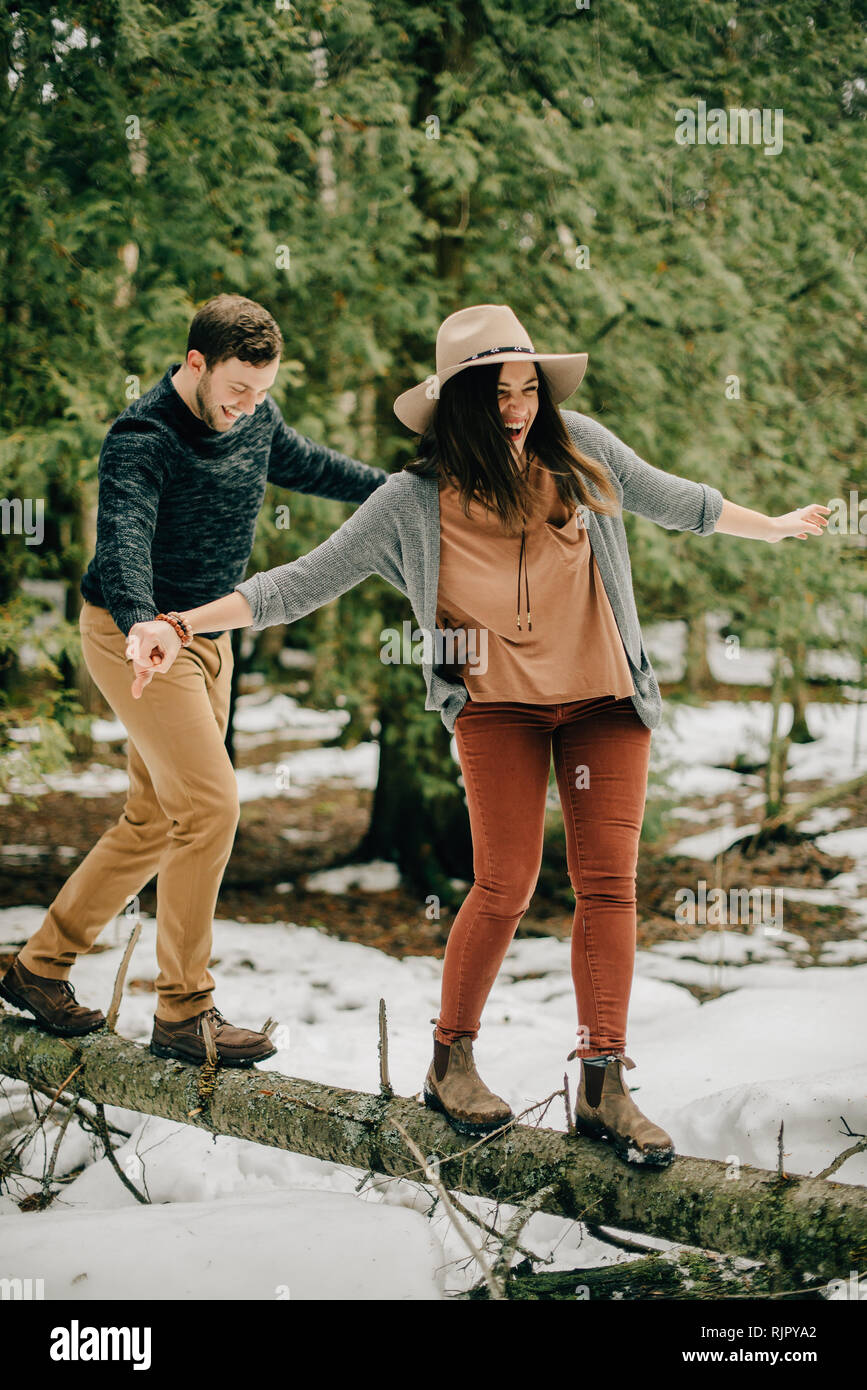 Couple balancing on fallen tree trunk in forest, Tobermory, Canada ...