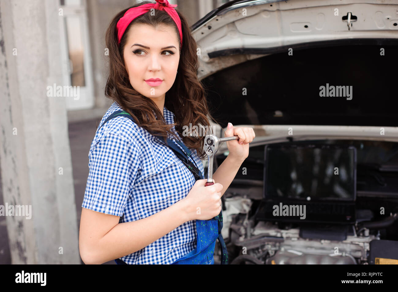 Cute attractive girl examining car engine at the auto repair sho Stock ...