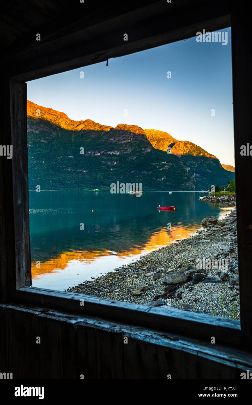 Looking through square cabin window at view of sunset over lake and ...