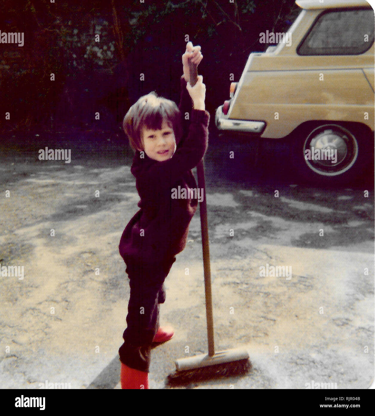 1970s - A young boy with a broom poses in the garden next to a 1972 ...