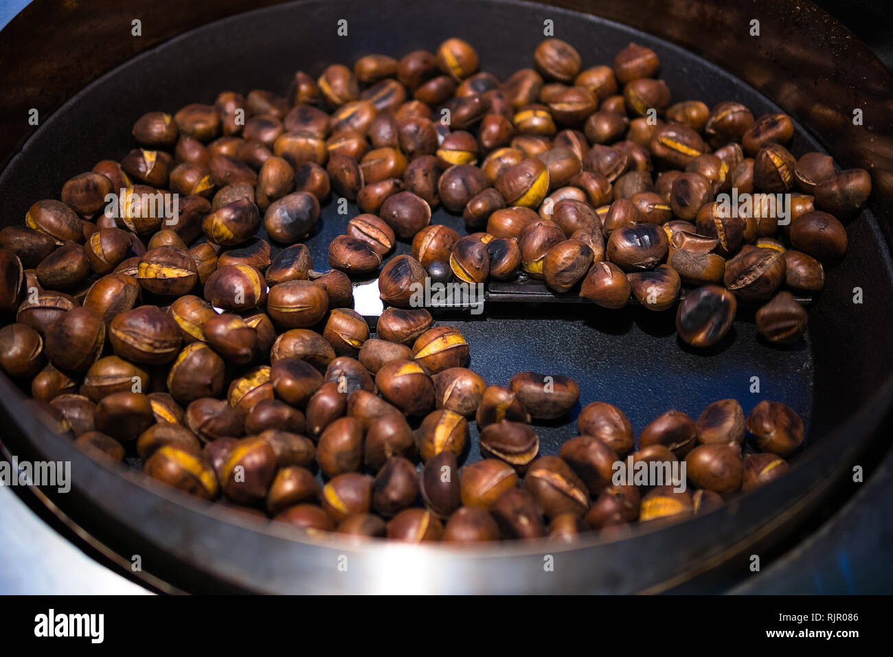 Brown roasted chestnuts roasting in the pan. Selling nuts on Christmas ...