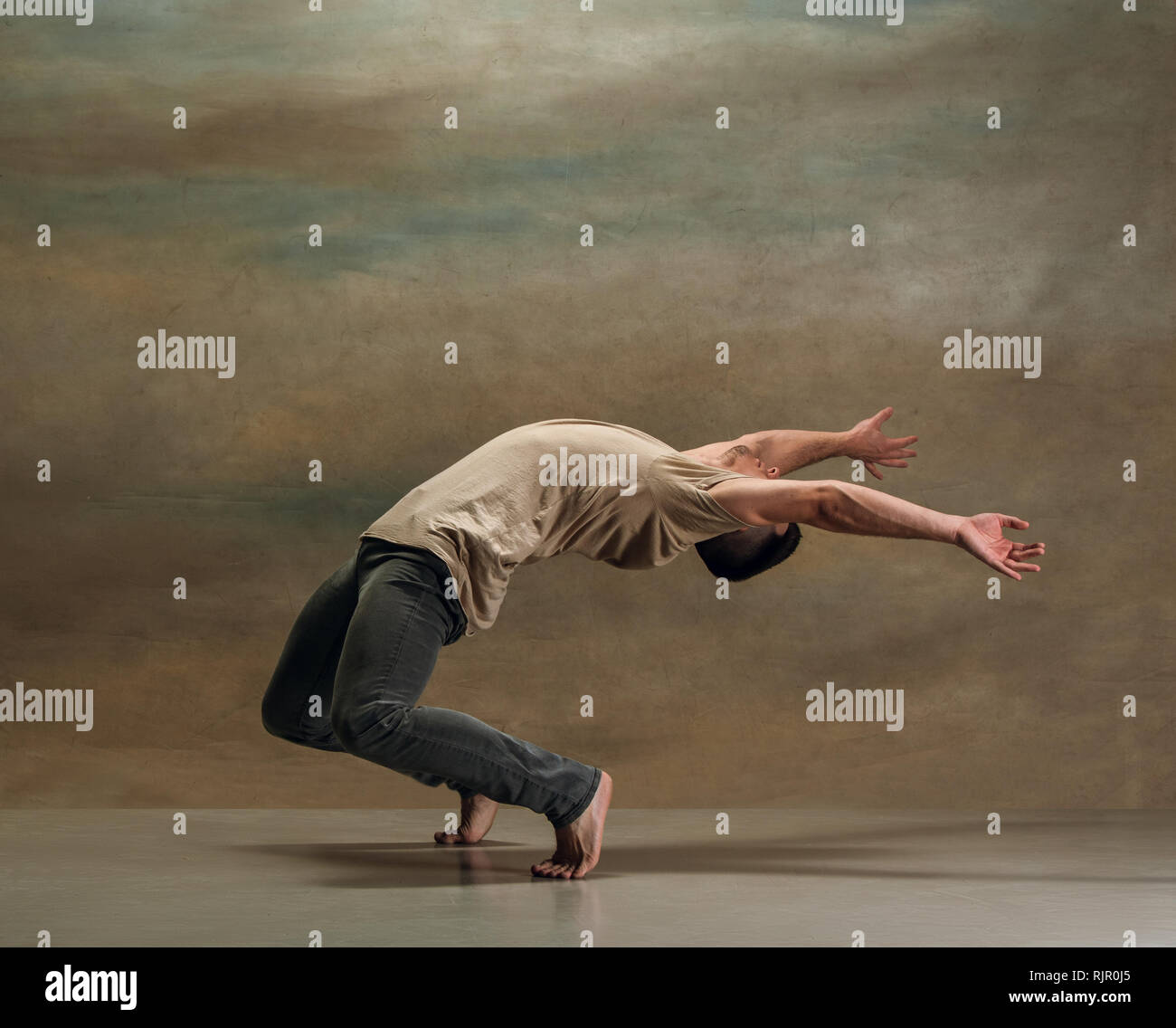 The young man dancing in contemporary stile of ballet at studio on gray ...