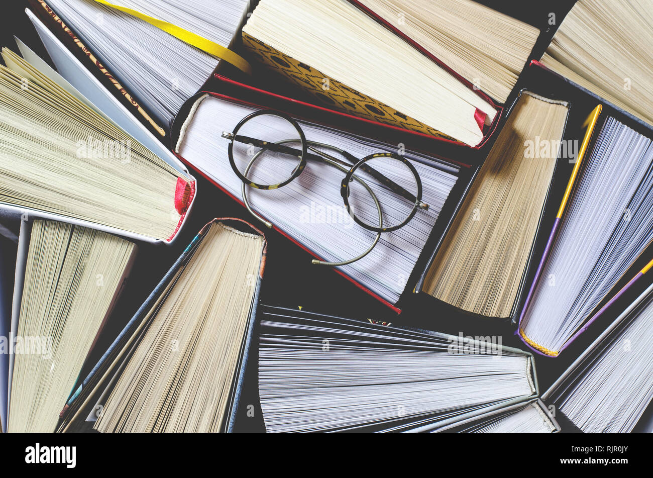 Many multicolored thick open books stand on a dark background. On the ...