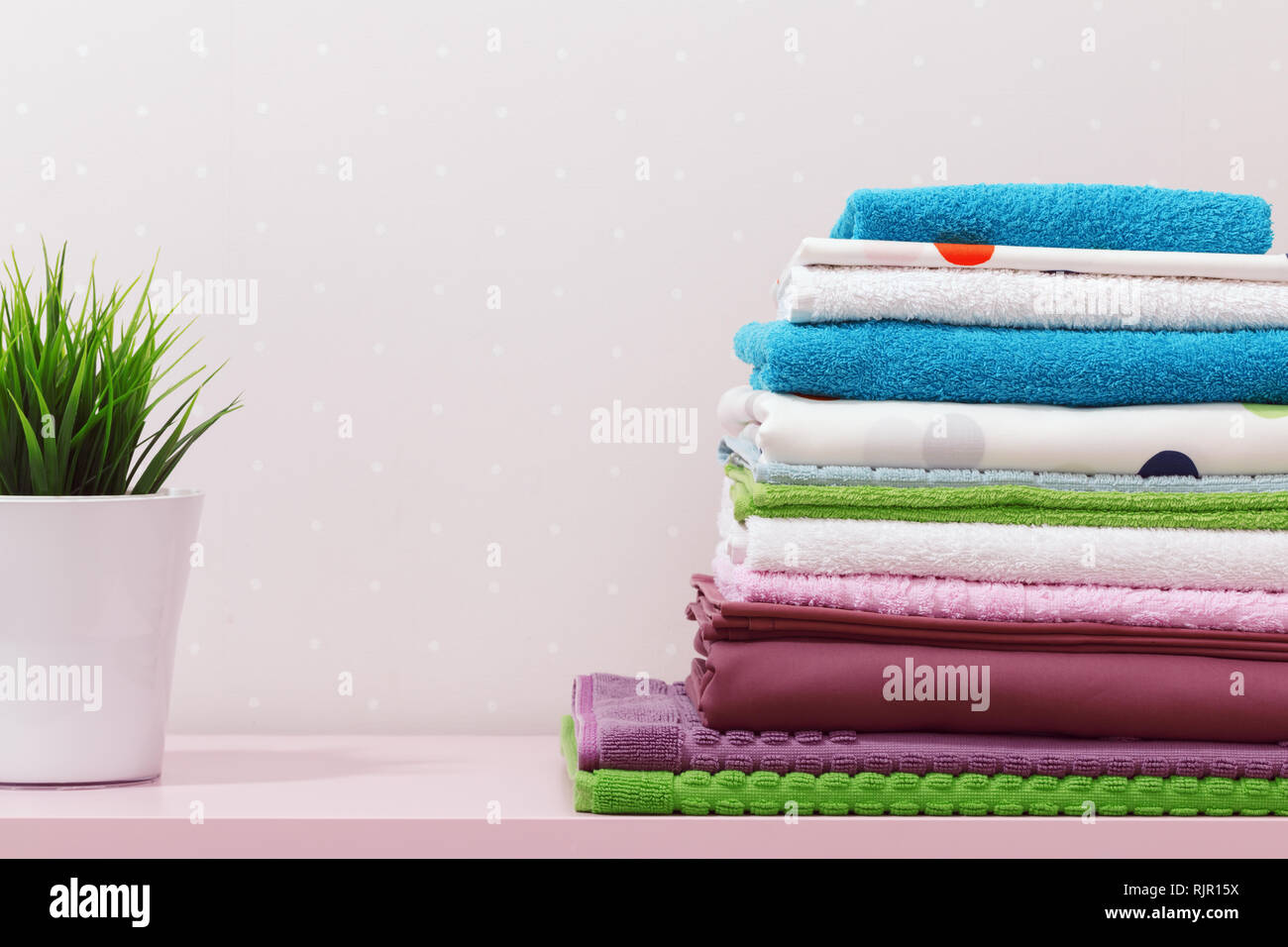 On the dresser there is a stack of clean ironed bed linen, folded multi ...