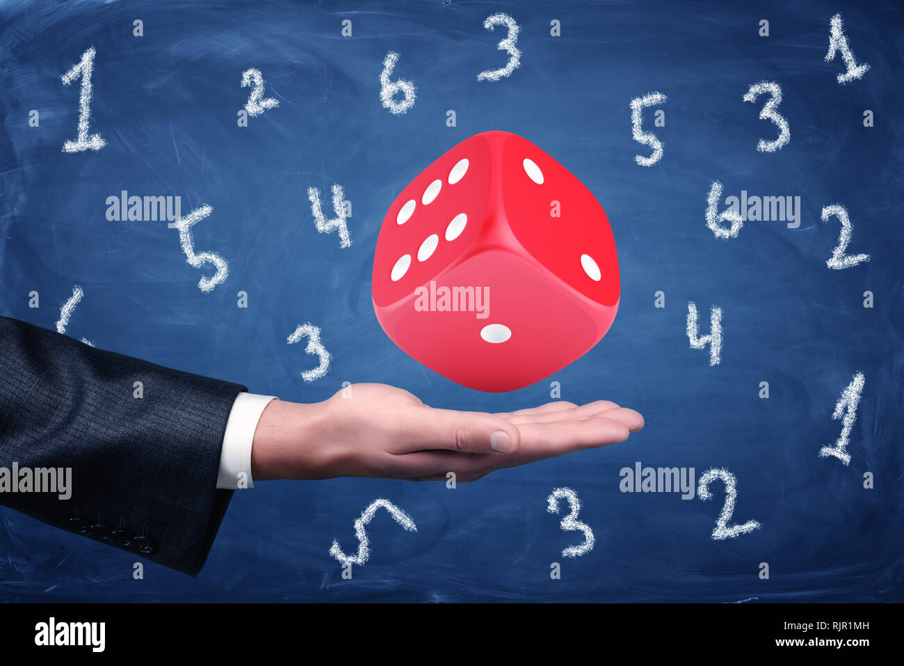 Businessman hand and big red dice with random numbers on blue ...