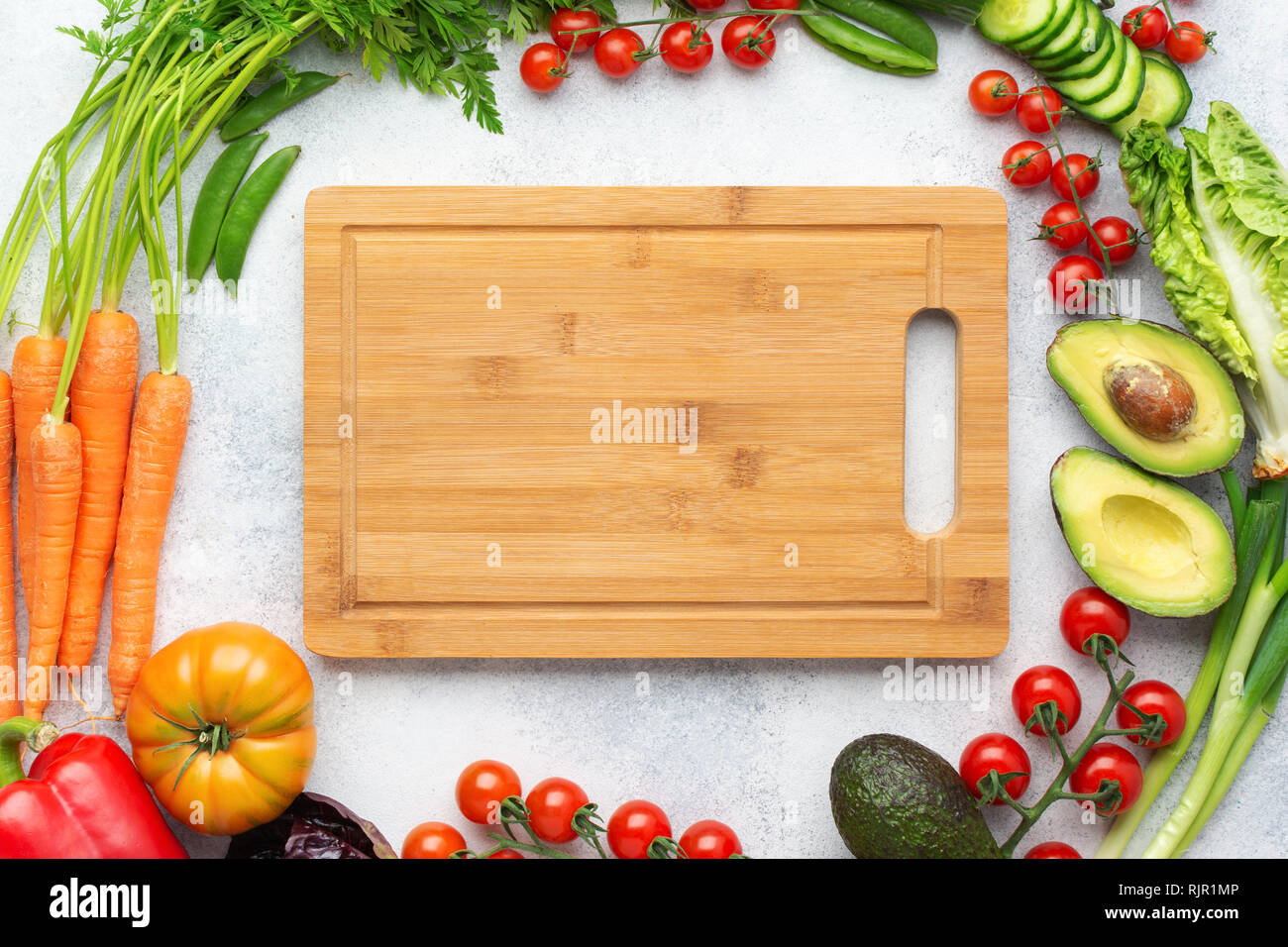 Fresh raw ingredients arranged in a circle with chopping board in the ...