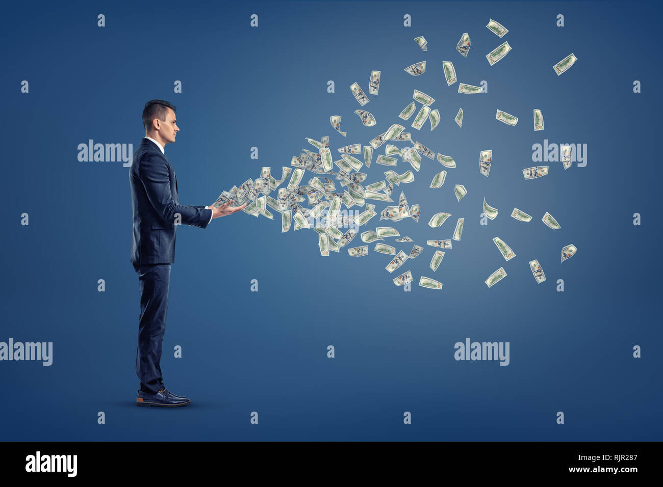 A single businessman stands in a side view with many USD dollar ...