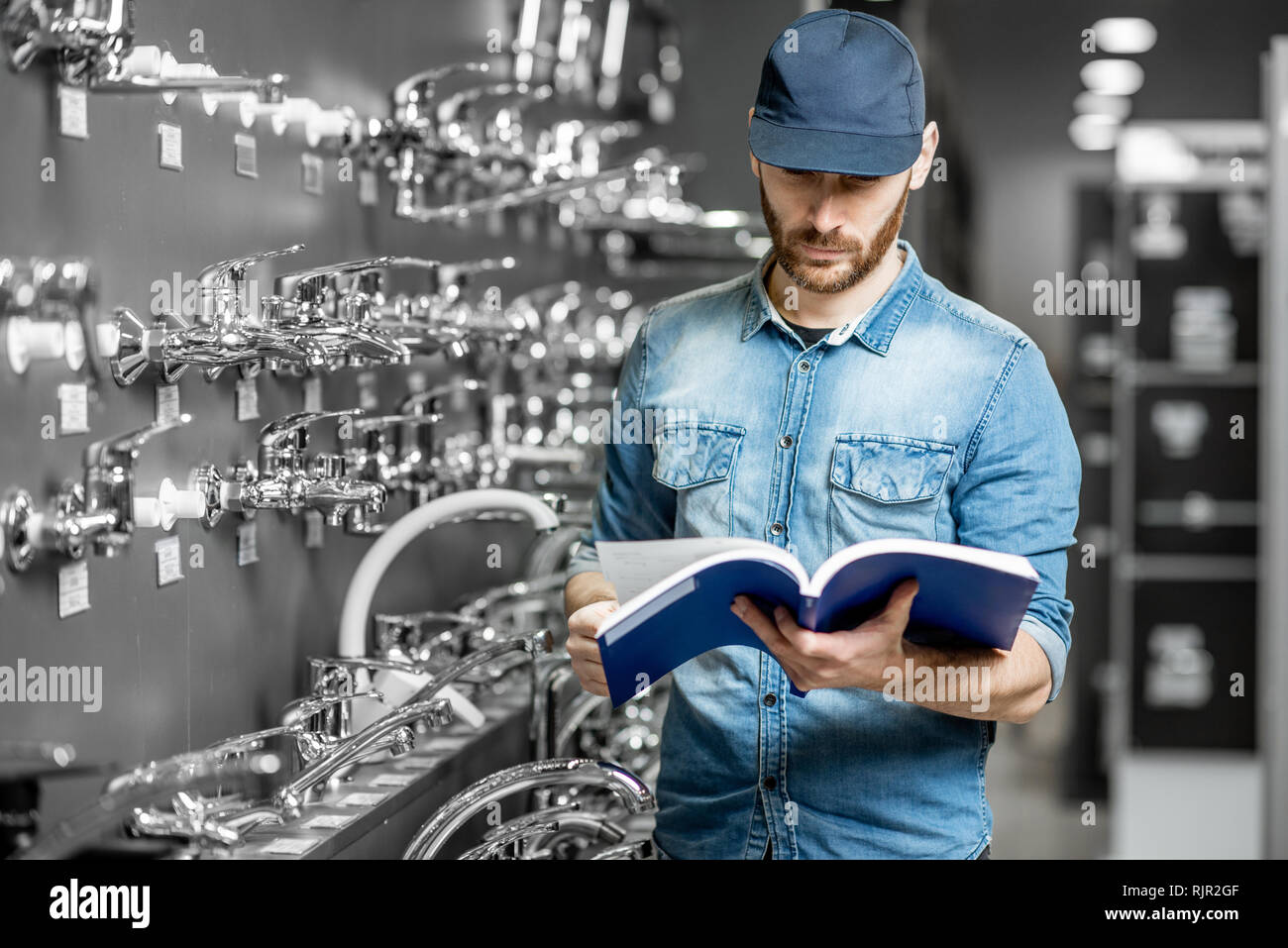 Handsome repairman or worker choosing sanitary taps standing with ...