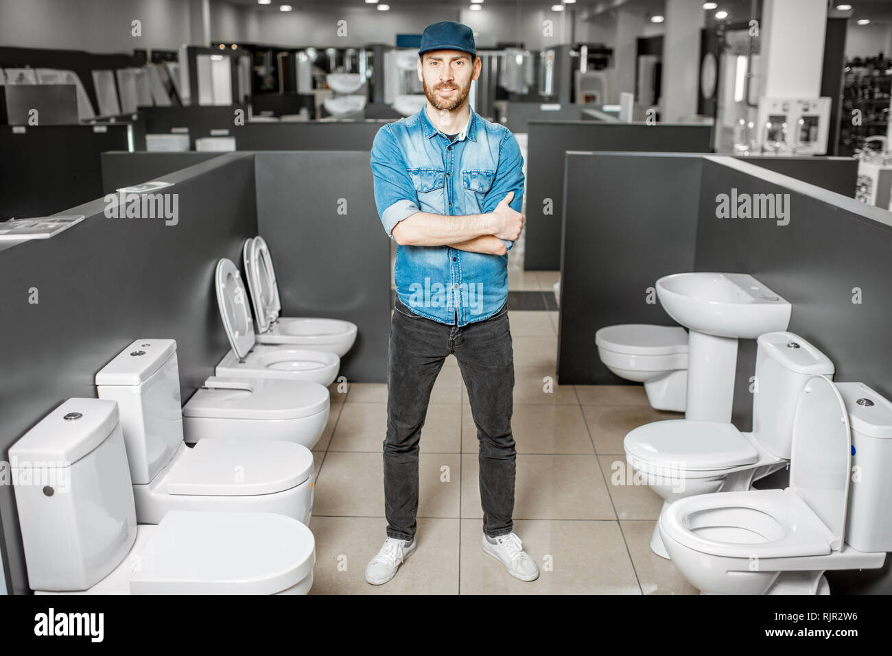 Handsome man as a worker choosing lavatory pan standing in the building ...