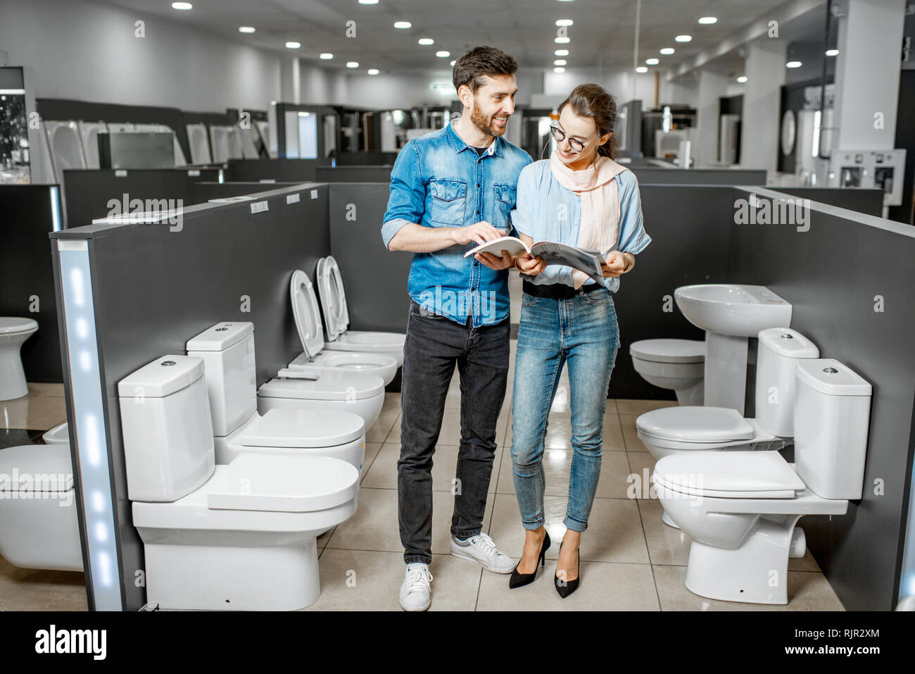 Young couple choosing lavatory pan standing together in the building ...