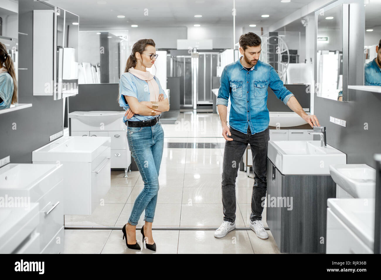 Young couple choosing new bathroom furniture at the plumbing shop with ...