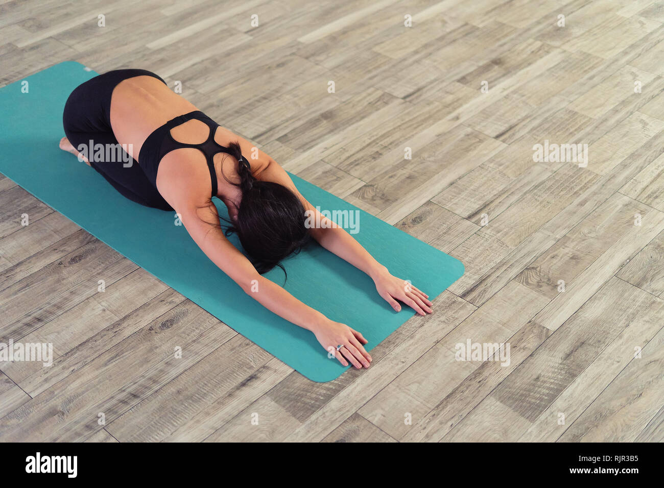 Woman practicing yoga, resting in child pose on the yoga mat. Copy ...