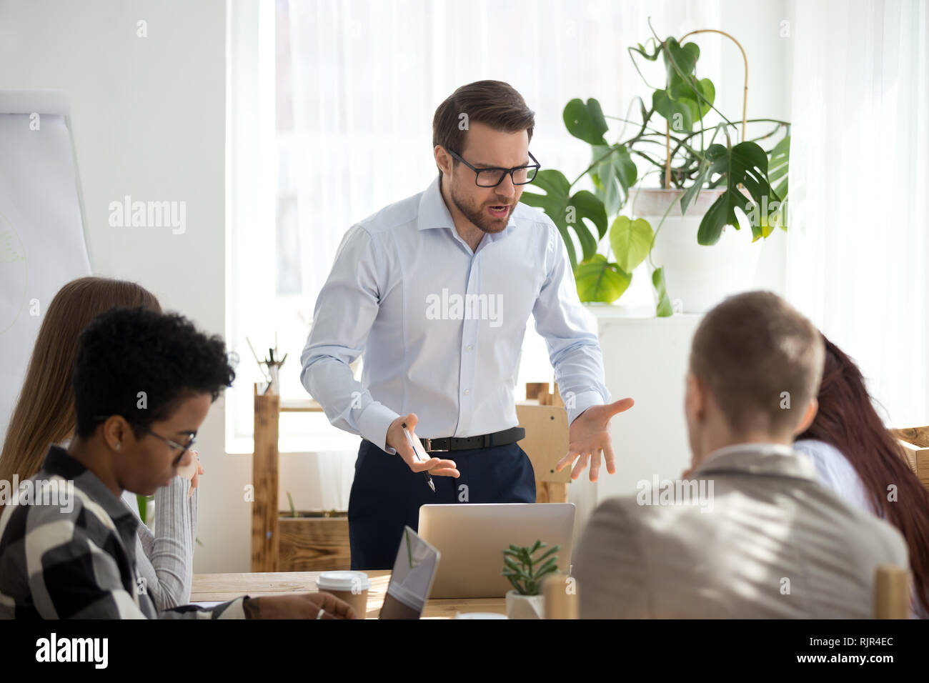 Angry manager boss shouting at group office meeting scolding employees ...