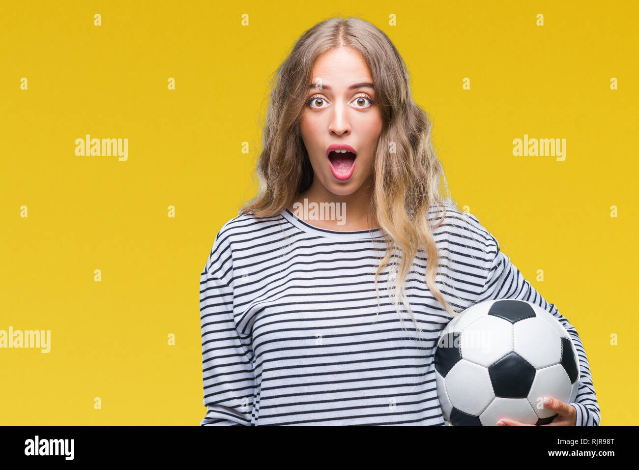 Beautiful young blonde woman holding soccer football ball over isolated ...