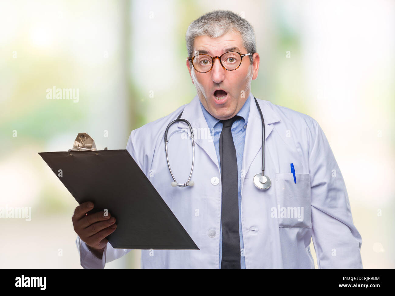 Handsome senior doctor man holding clipboard over isolated background ...