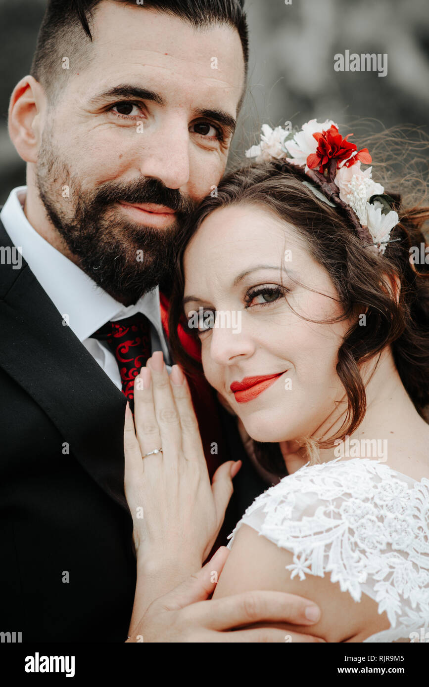 The bride and groom leaned against each other. They look at the camera ...