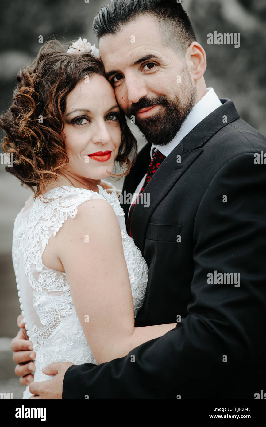 The bride and groom leaned against each other. They look at the camera ...