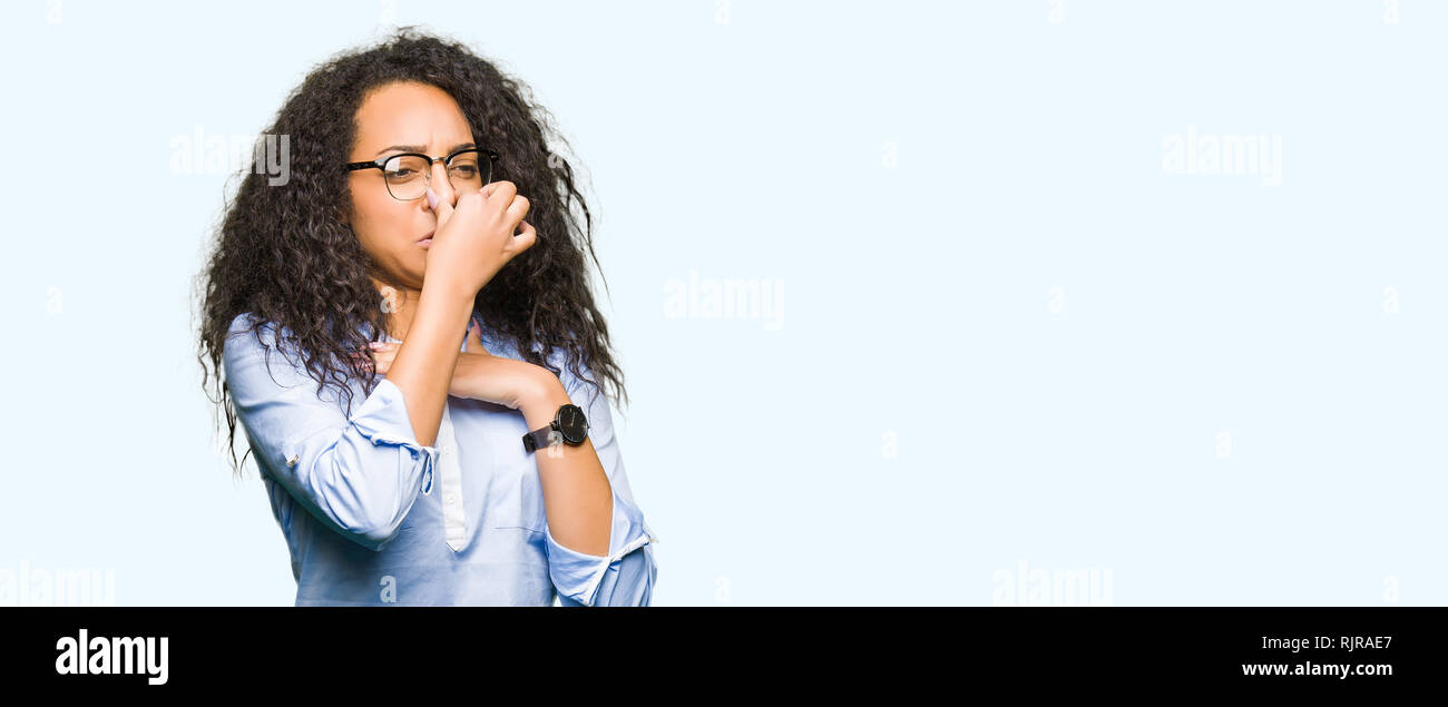 Young beautiful business girl with curly hair wearing glasses smelling ...