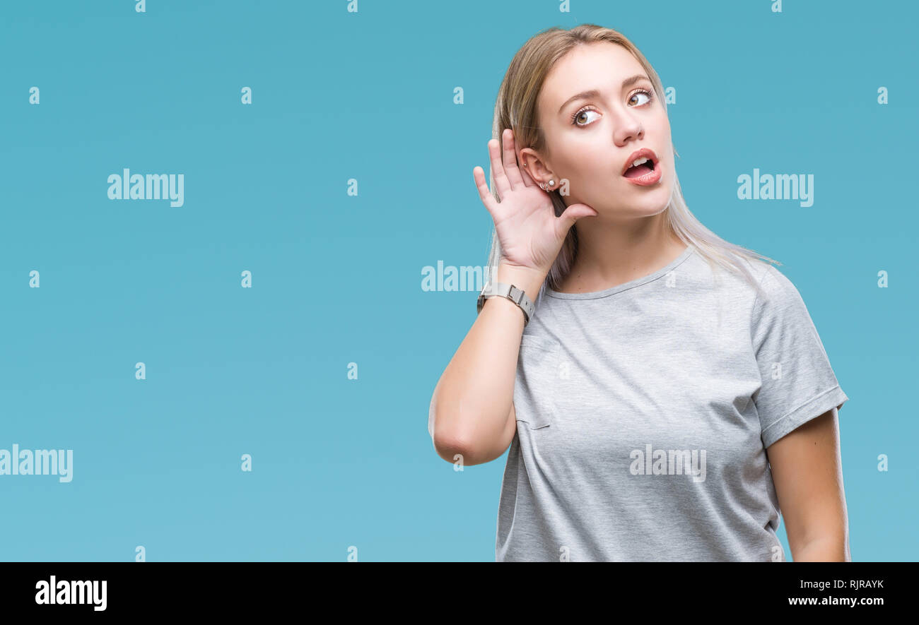 Young blonde woman over isolated background smiling with hand over ear ...