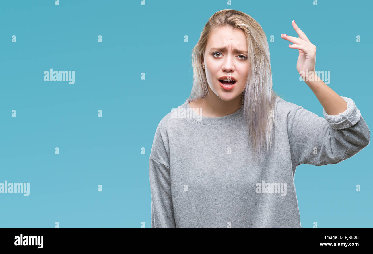 Young blonde woman over isolated background angry and mad raising fist ...