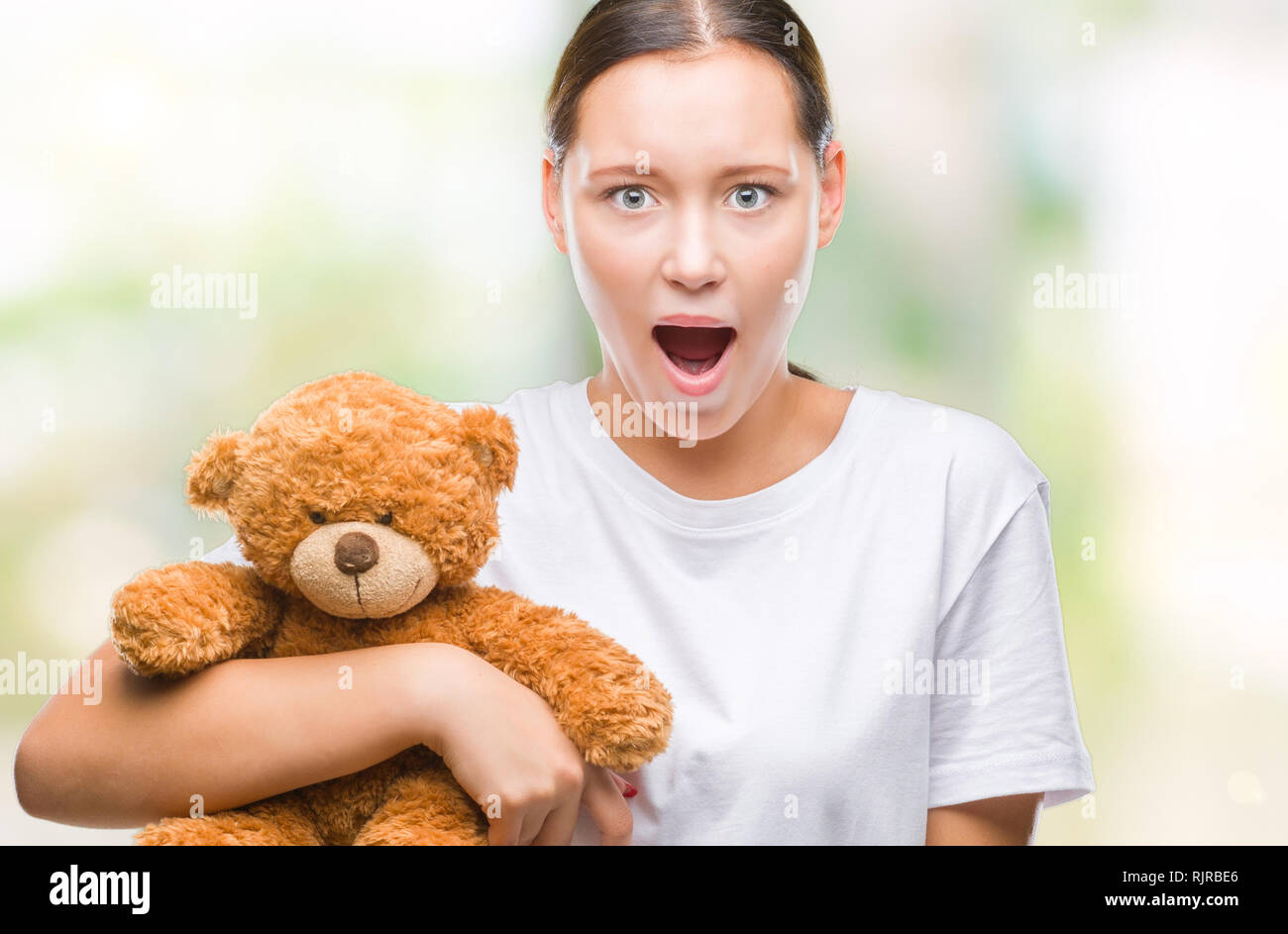 Young caucasian woman holding teddy bear over isolated background ...