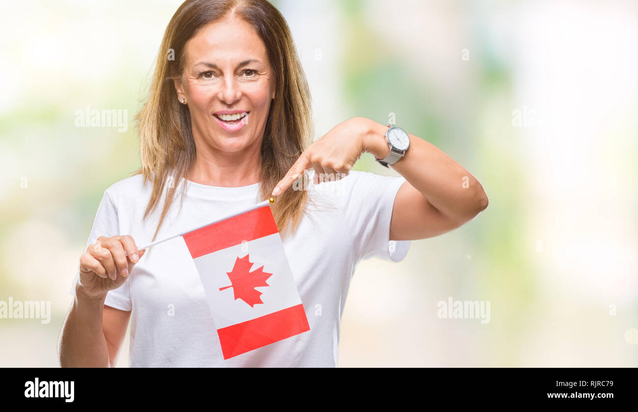 Middle age hispanic woman holding flag of Canada over isolated ...