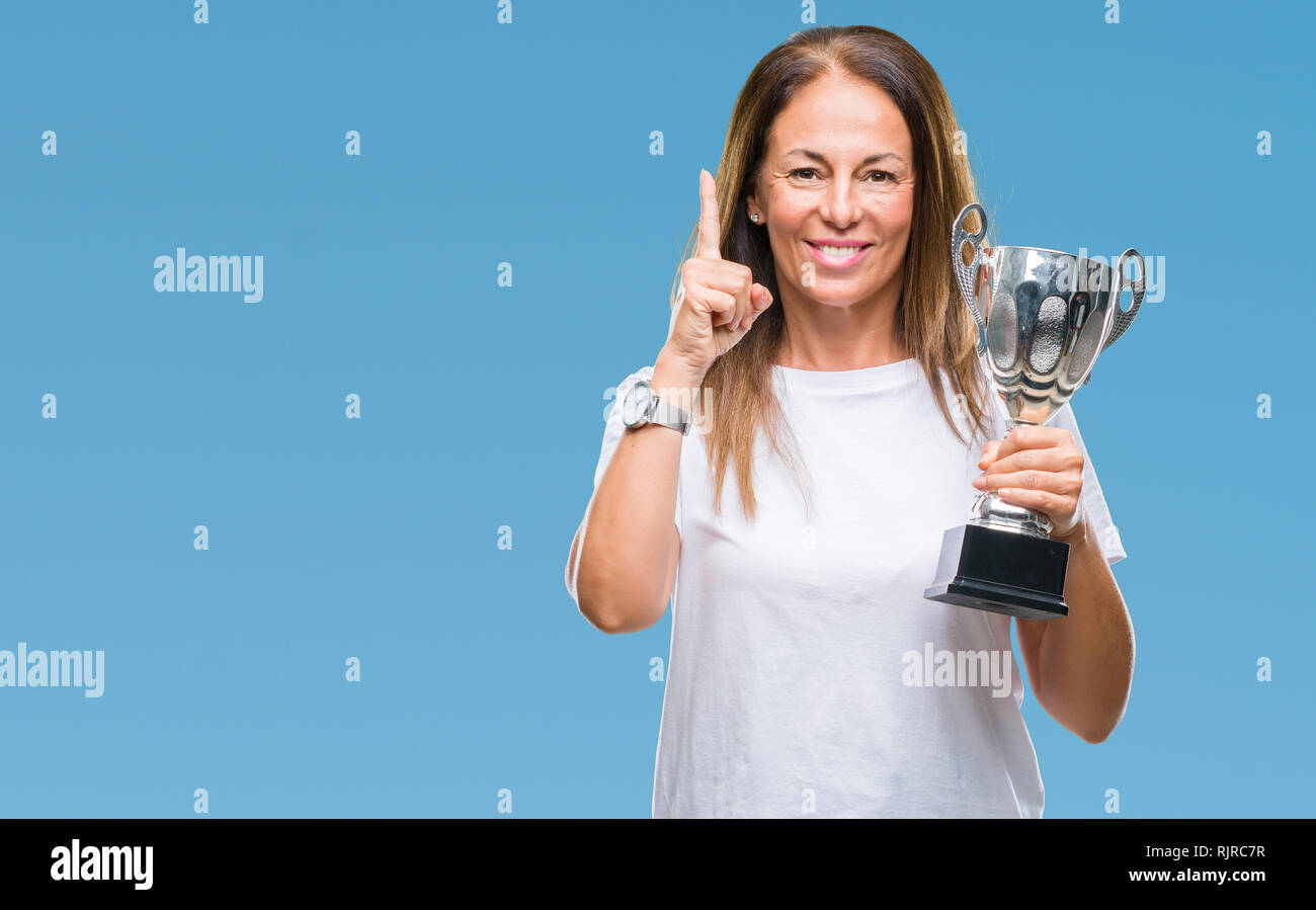 Middle age hispanic winner woman celebrating award holding trophy over ...