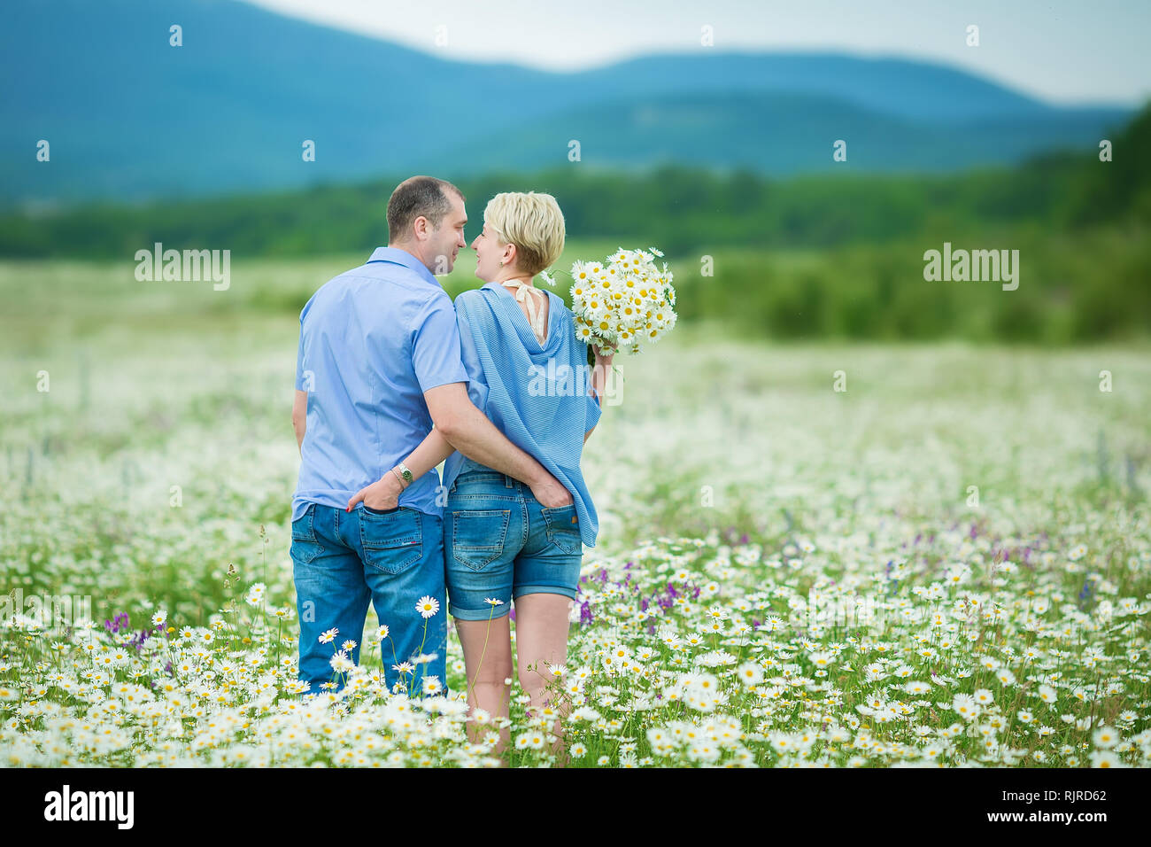 Romantic couple hugging and breathing fresh air in a warm field with ...