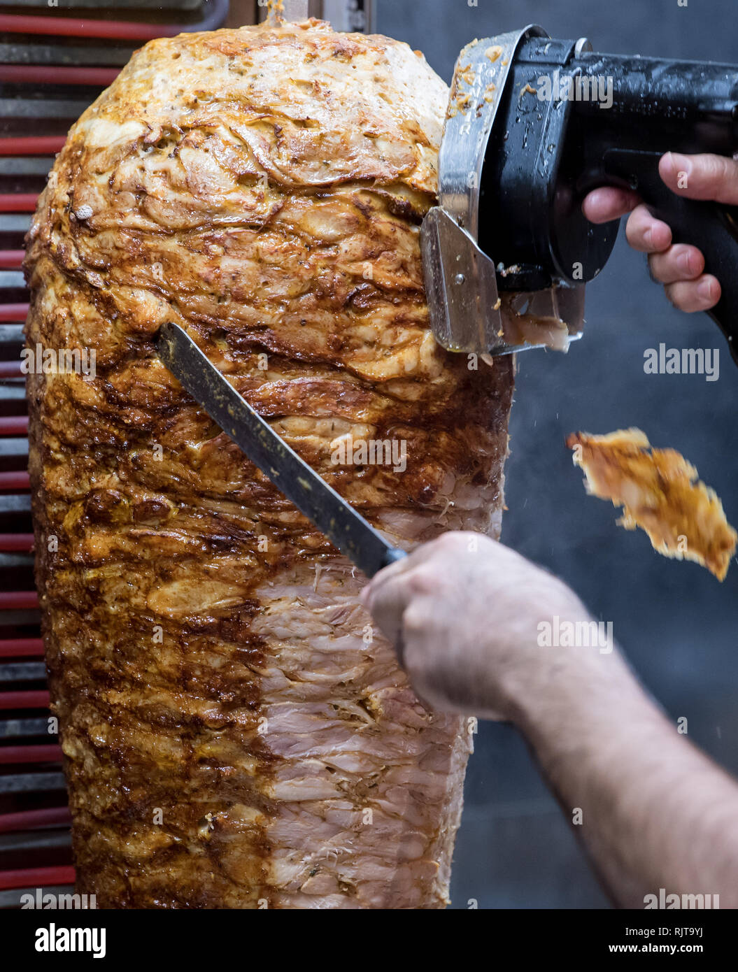 07 February 2019, Bavaria, München: A man cuts meat from a kebab skewer ...