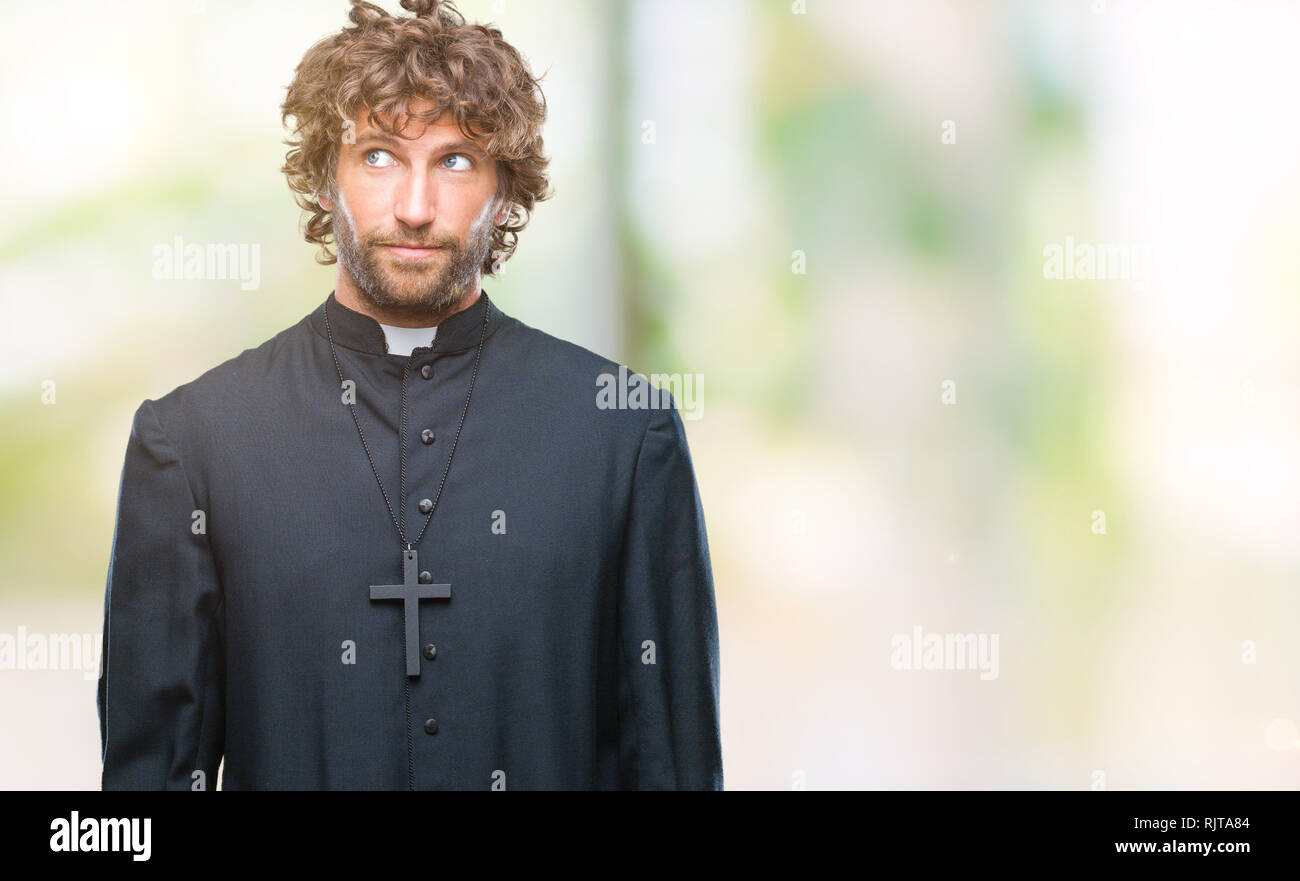 Handsome hispanic catholic priest man over isolated background smiling ...