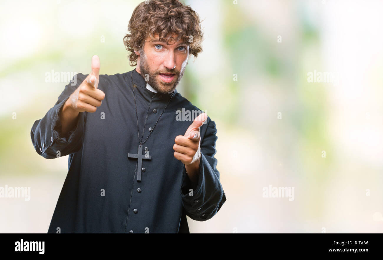 Handsome hispanic catholic priest man over isolated background pointing ...