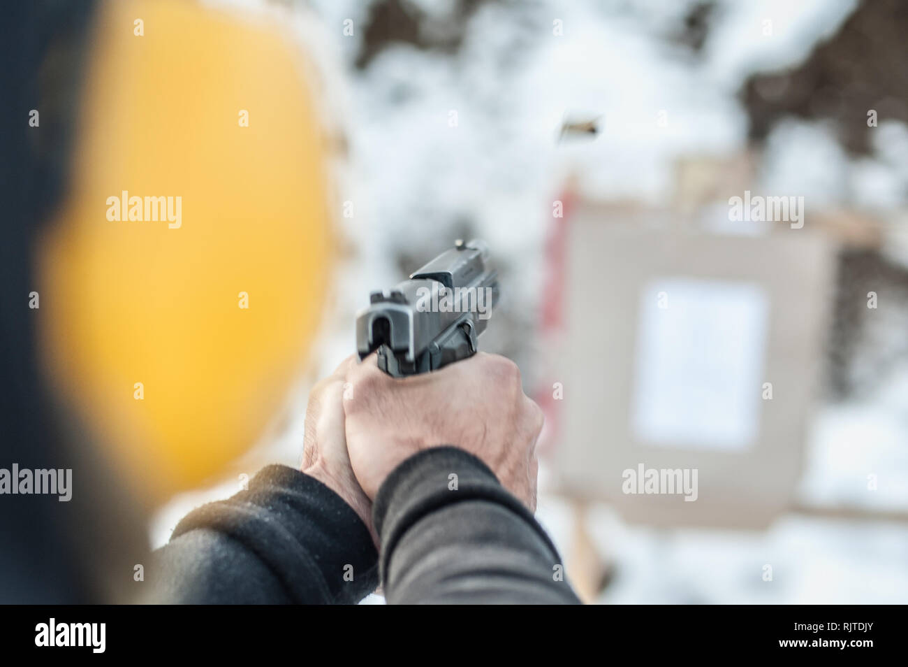 Detail back view of shooter holding gun in hand and shooting on target ...