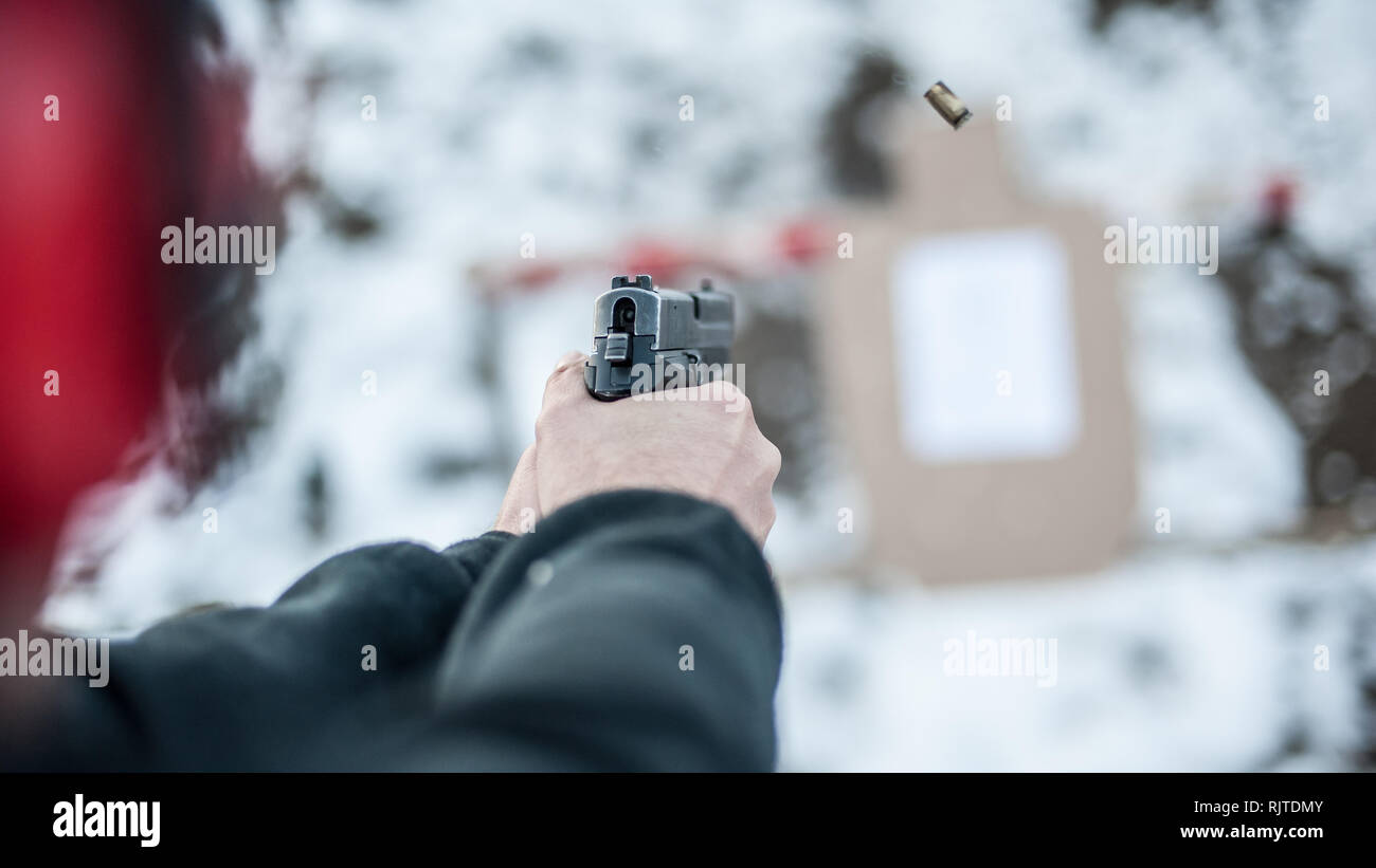 Detail back view of shooter holding gun in hand and shooting on target ...