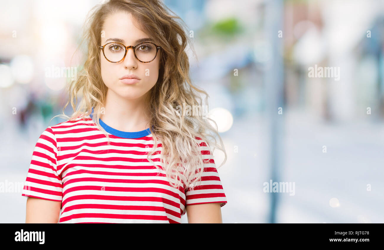 Beautiful young blonde woman wearing glasses over isolated background ...