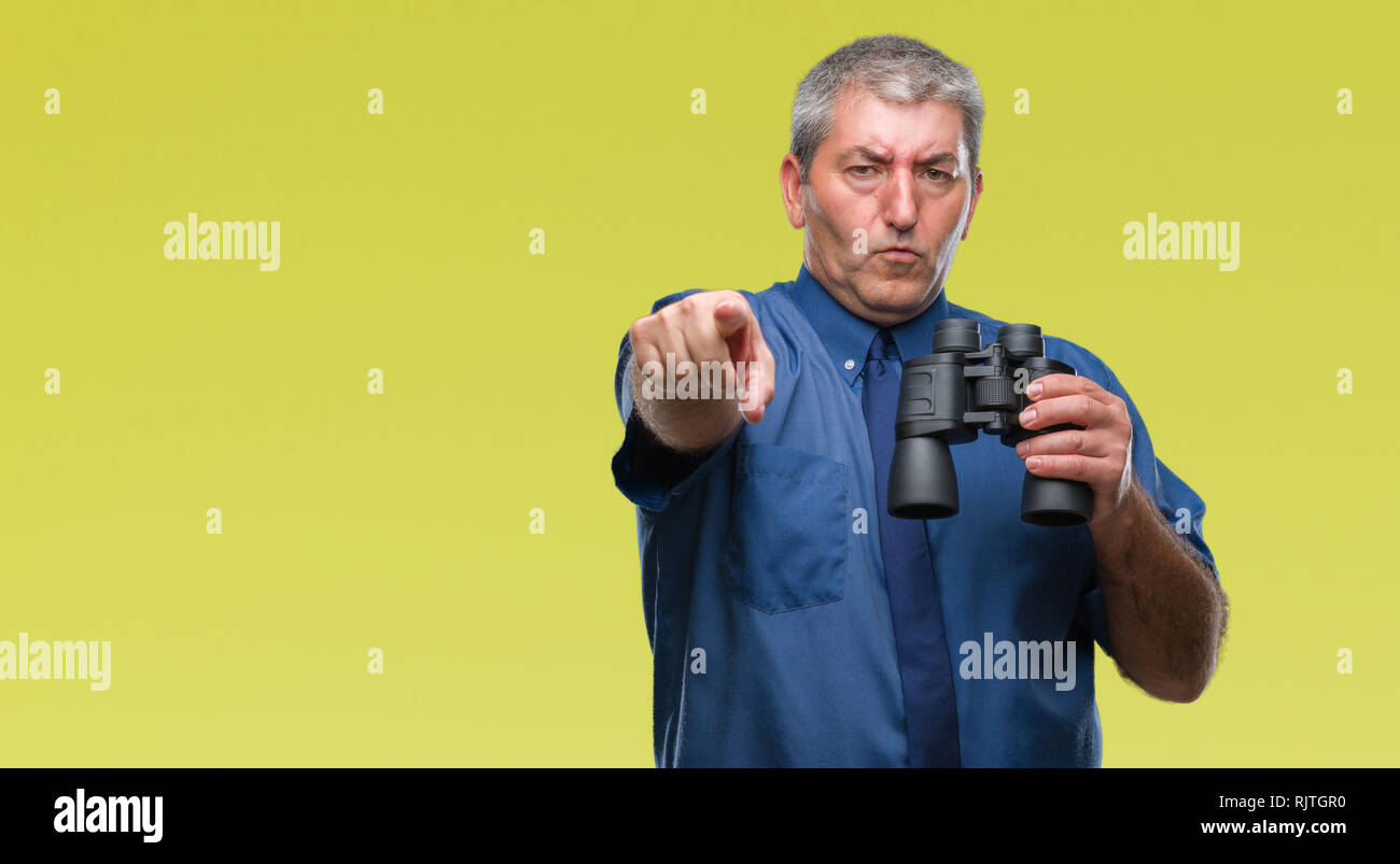 Handsome senior man looking through binoculars over isolated background ...