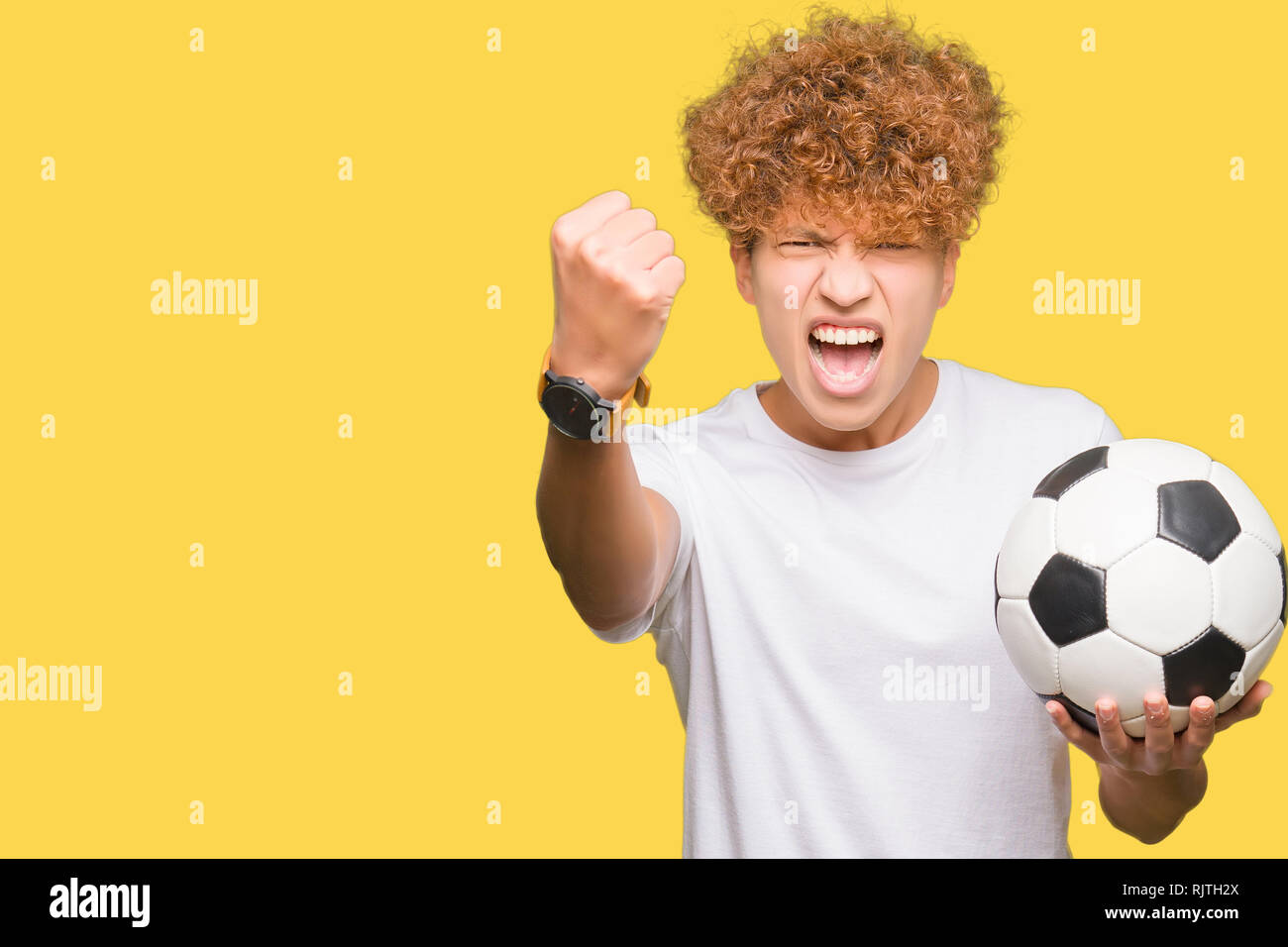 Young handsome man holding soccer football ball annoyed and frustrated ...