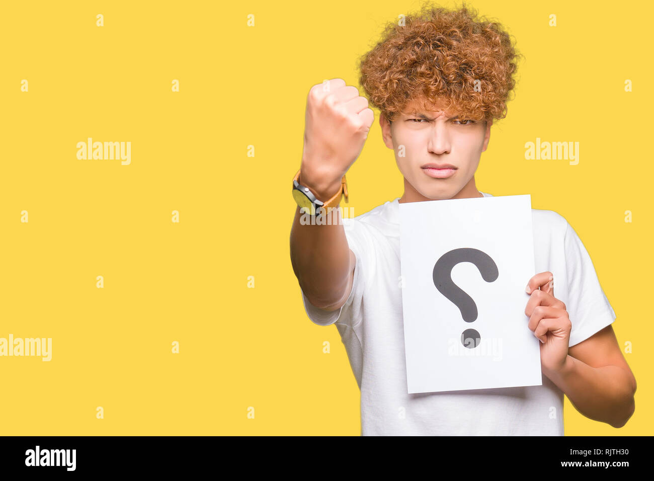 Young handsome man holding paper with question mark annoyed and ...